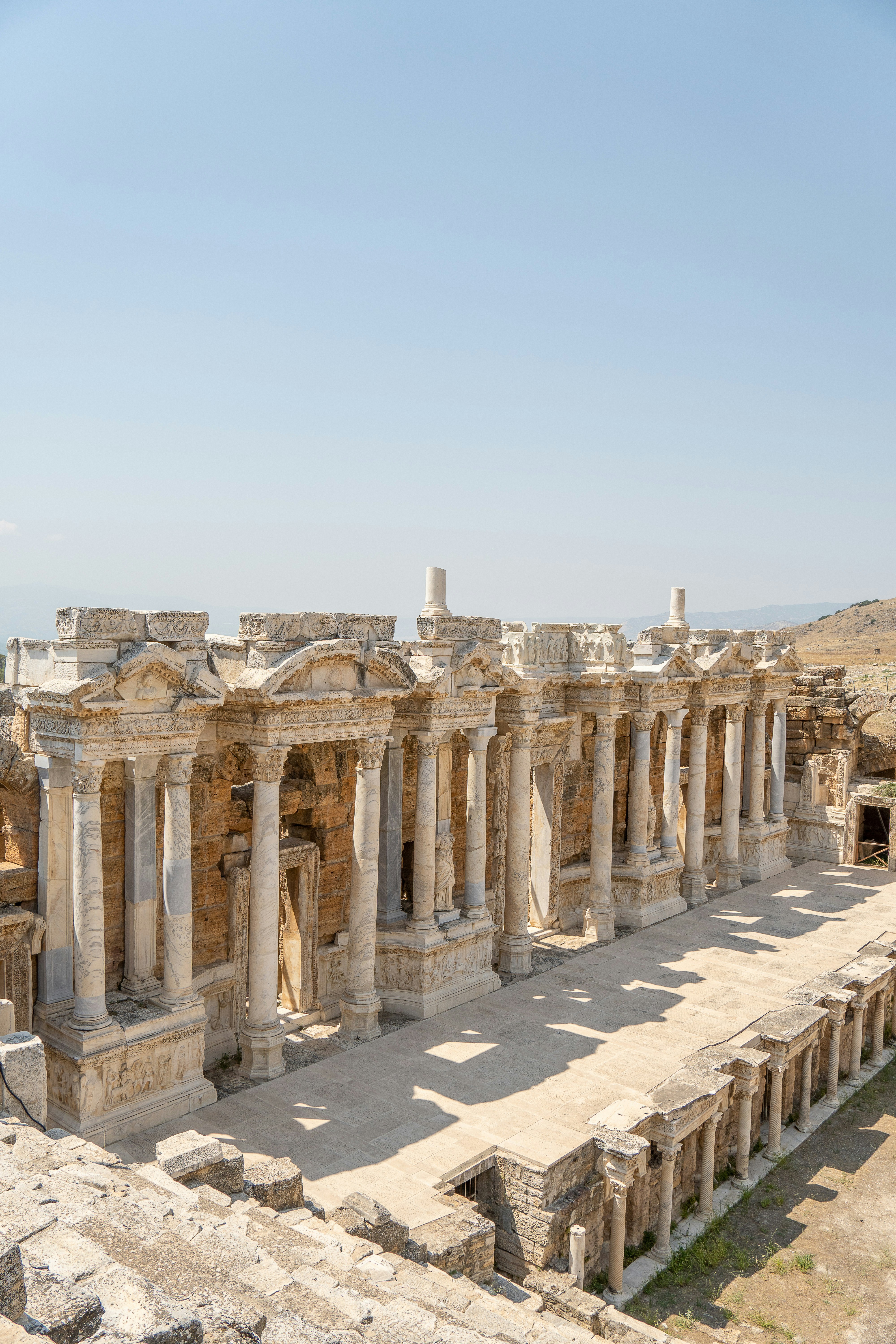 Ancient ruins featuring grand columns and a stone courtyard, showcasing the architectural legacy of a bygone civilization.