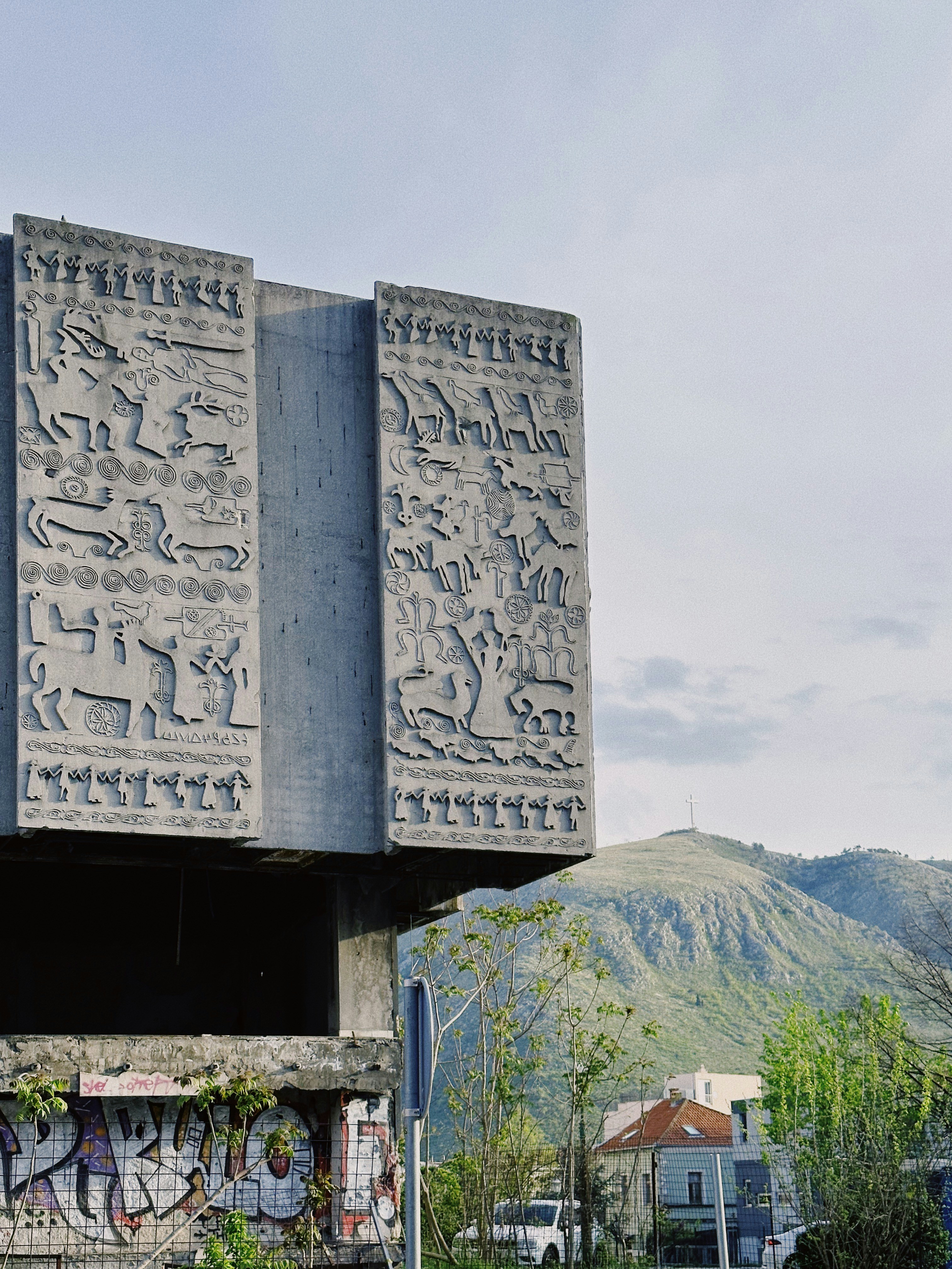 Monolithic Relief Panels Over Graffiti-Streaked Street