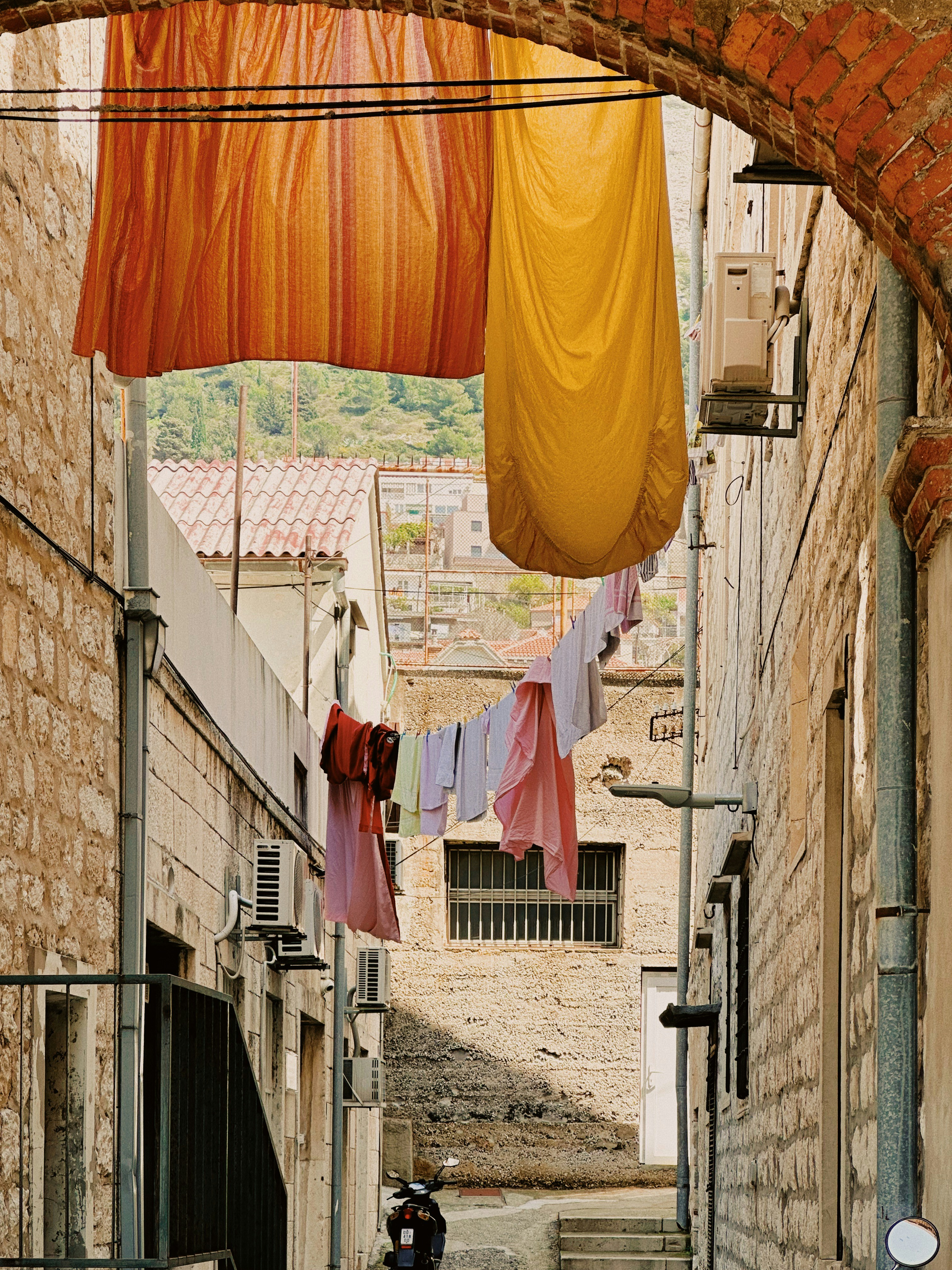 Sunlit Laundry Corridor: A Narrow Brick Alley Framed by Clothes