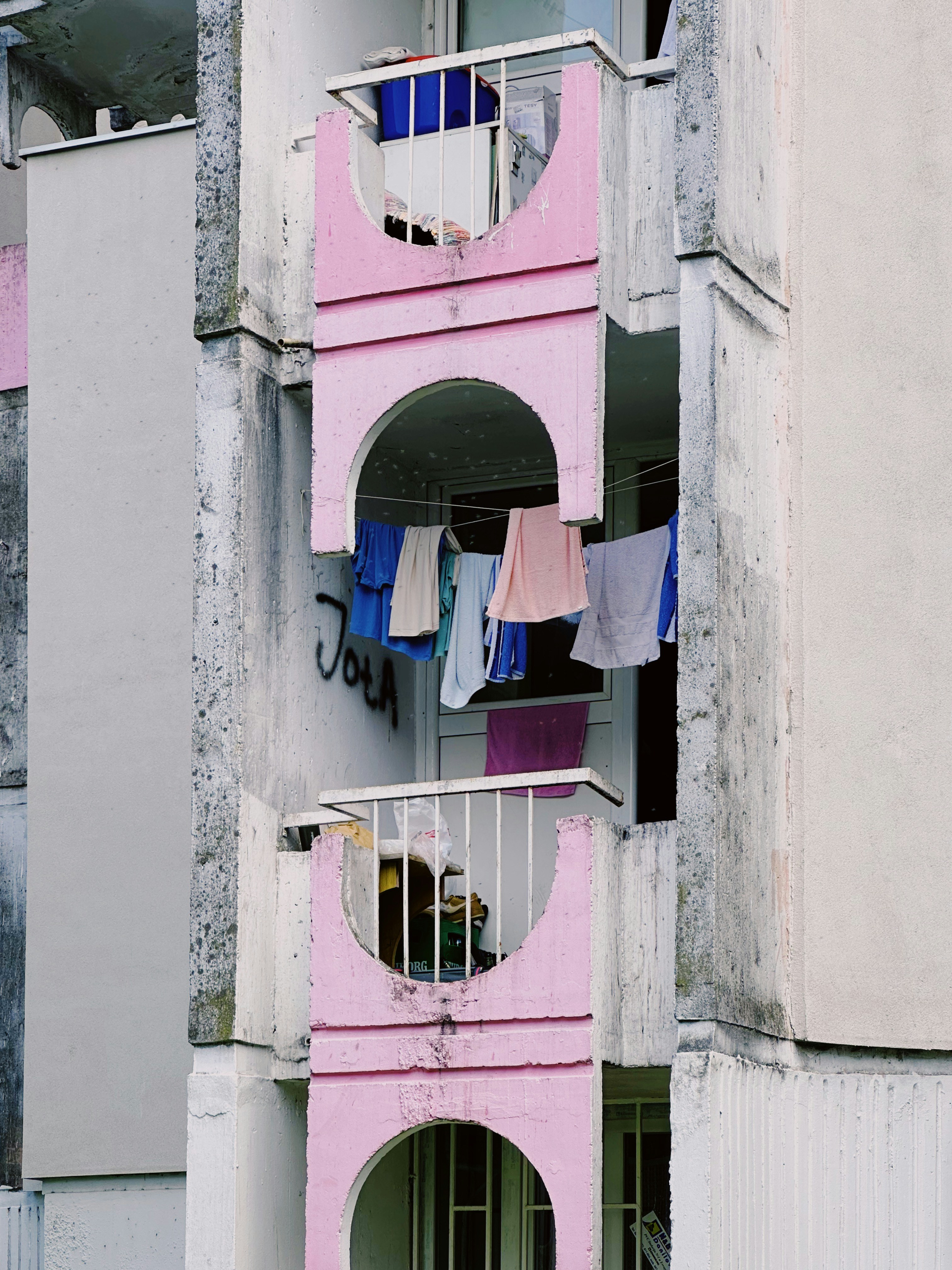 Vertical Pink Balconies: Laundry Strung Across Concrete Arches