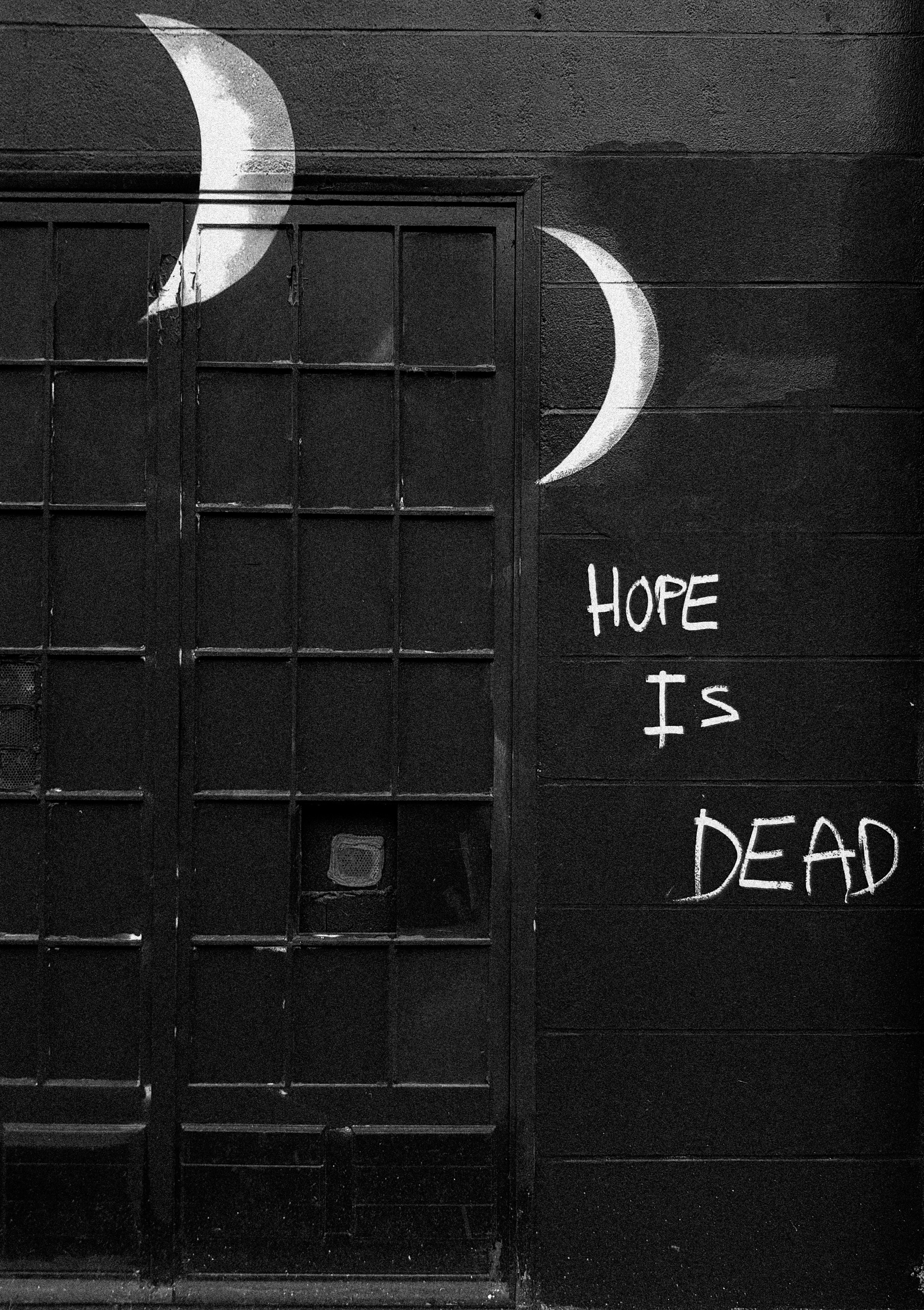 A black and white photo of a door with the words hope is dead written ...