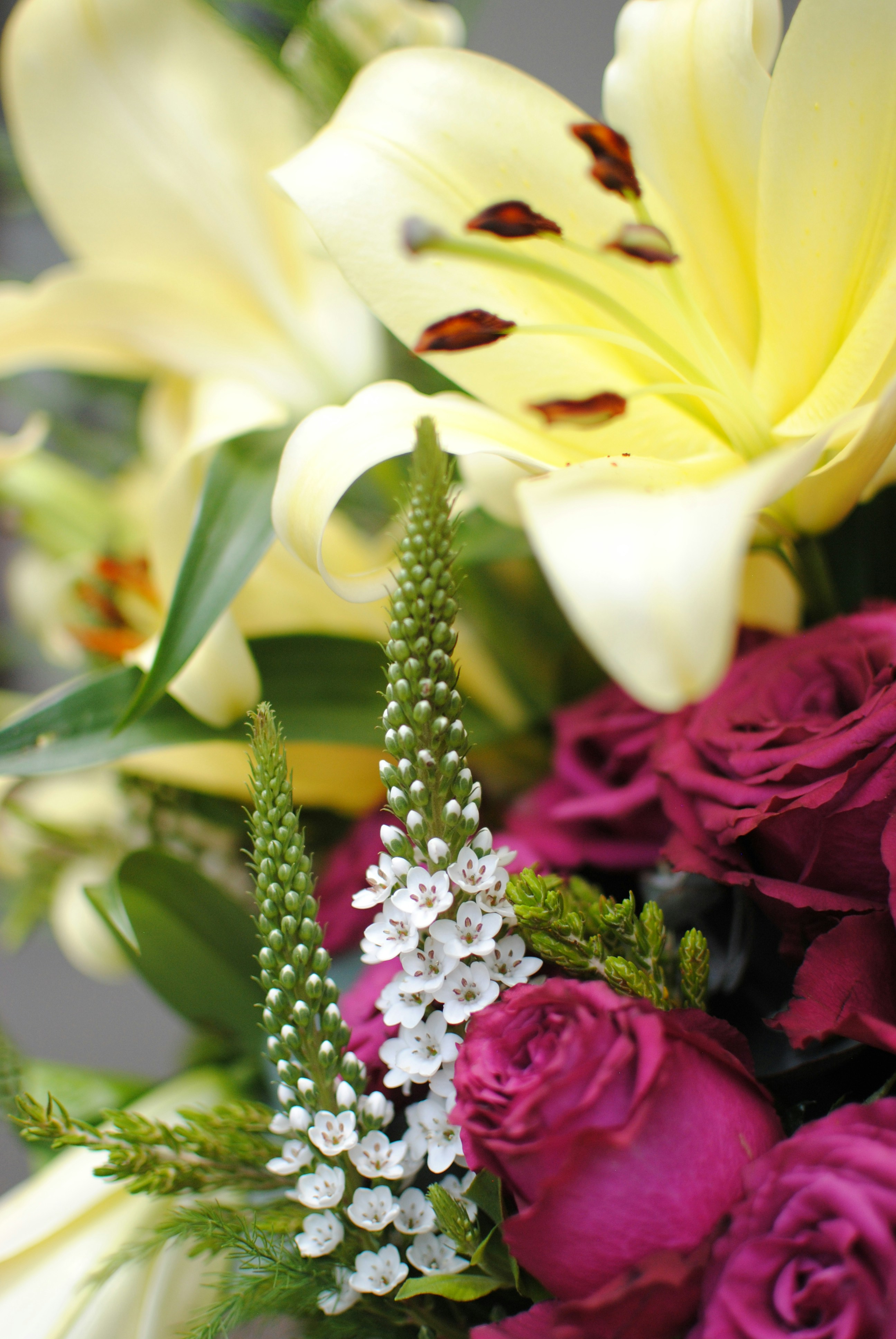Yellow lilies and magenta roses with white blossoms create a vibrant floral arrangement.
