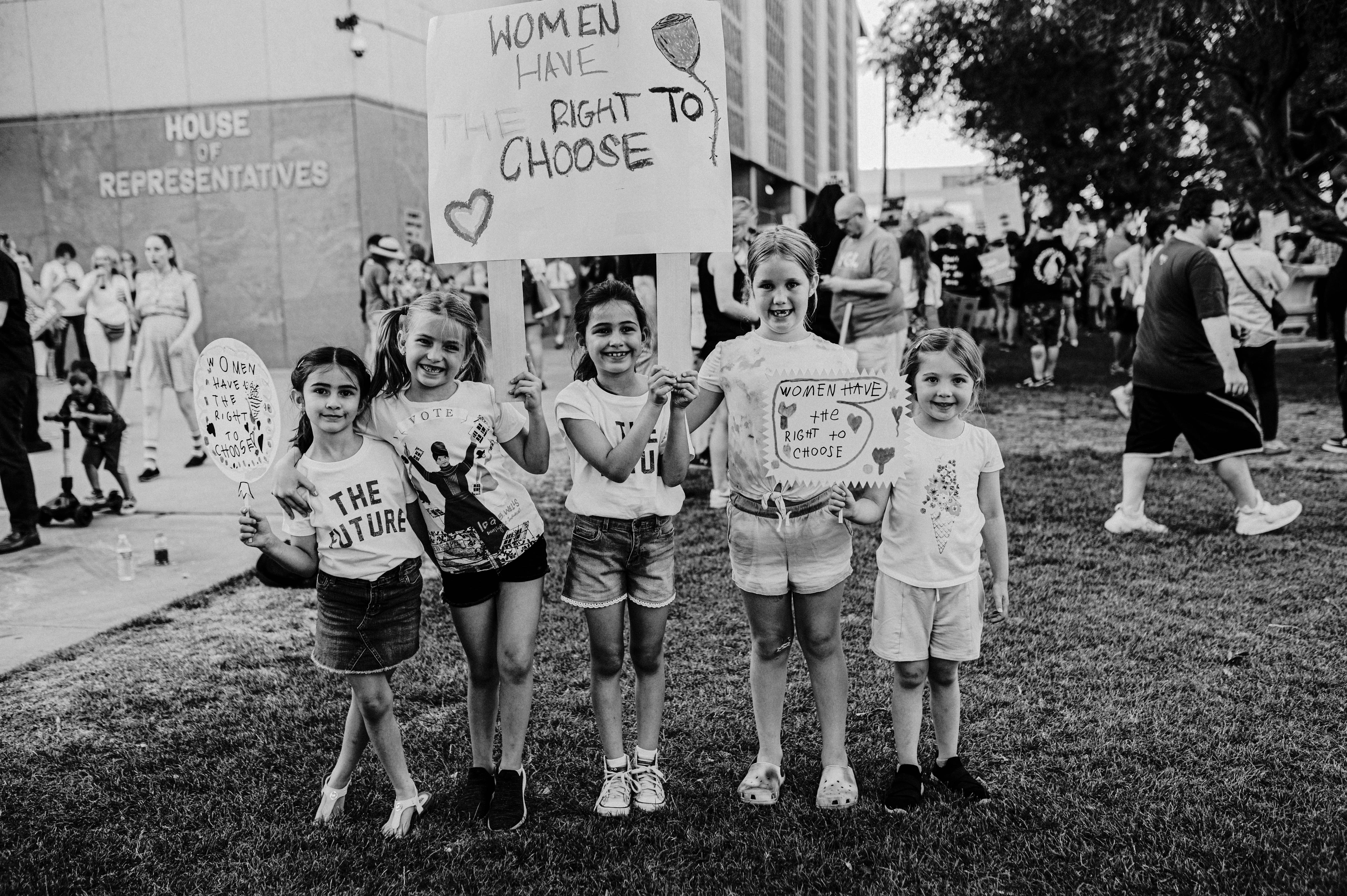 A group of young girls holding signs in front of a crowd photo – Free ...
