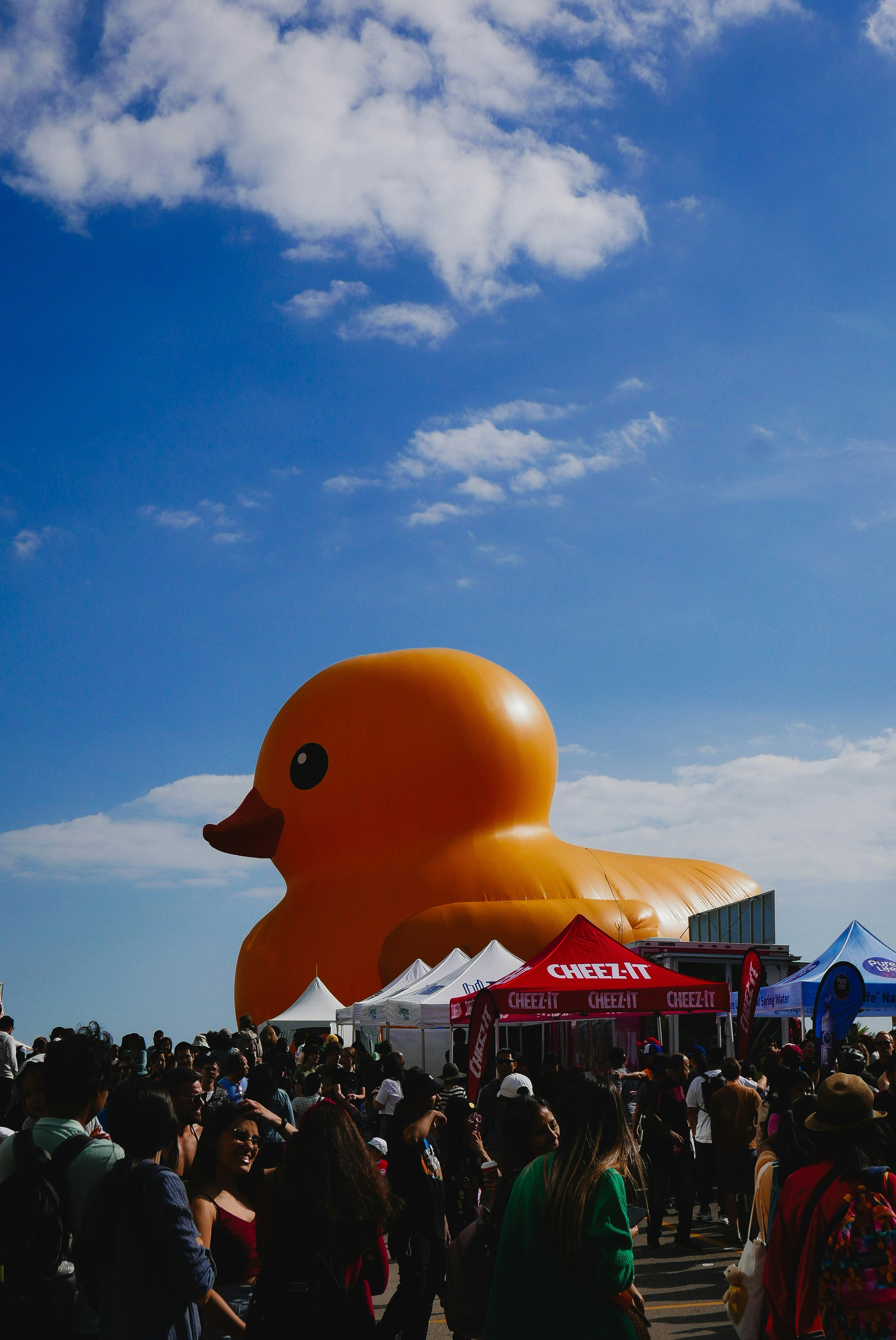 A large orange rubber duck floating over a crowd of people photo – Free ...