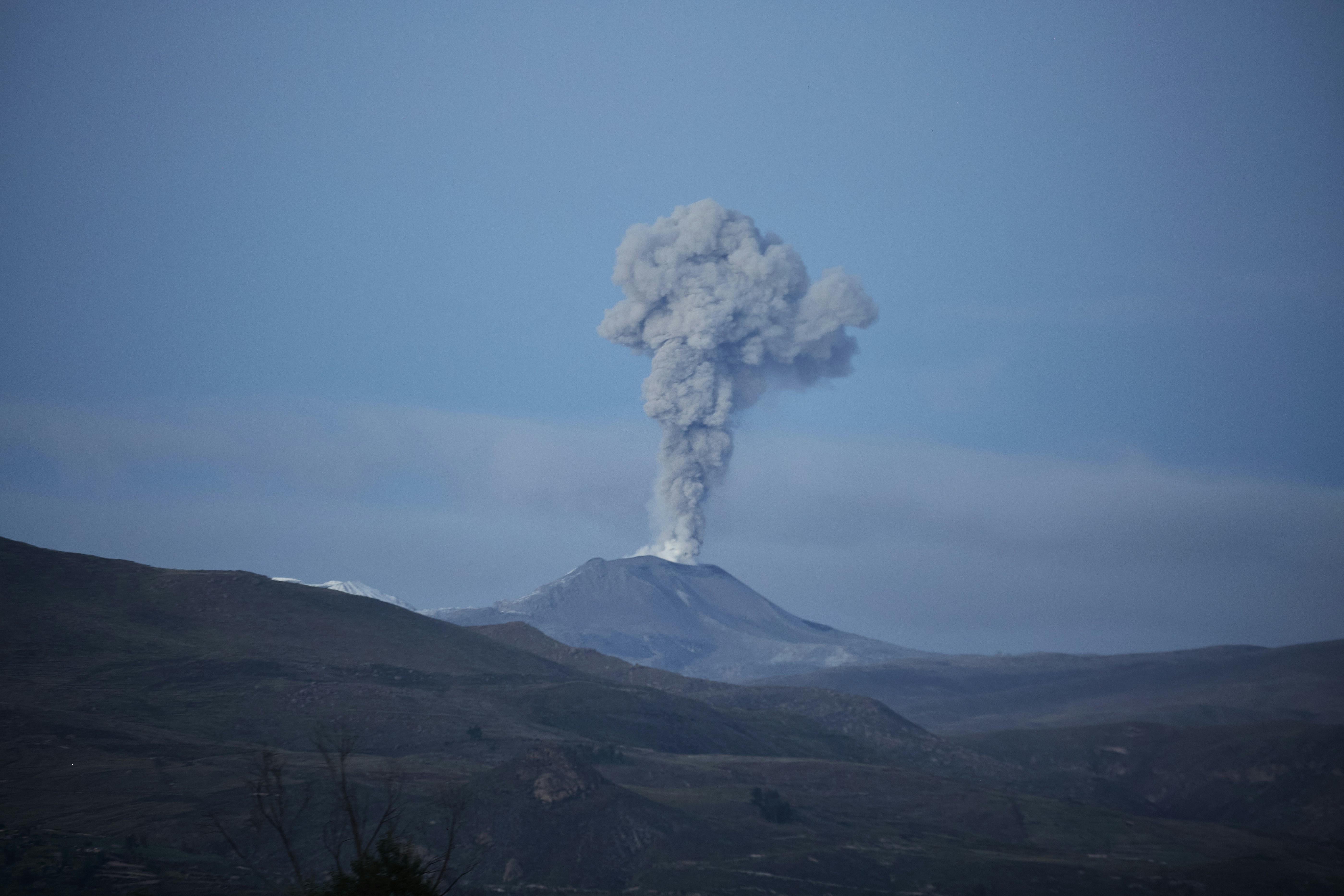 Dawn over a distant eruption: ash plume rises above the quiet highlands