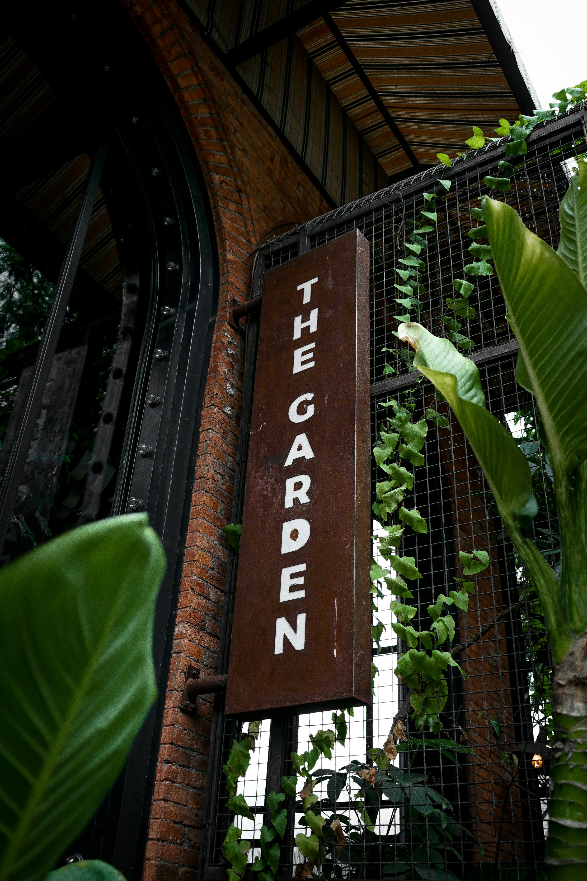 The Garden Gate: Rust, Brick and Vines Framing a Sign