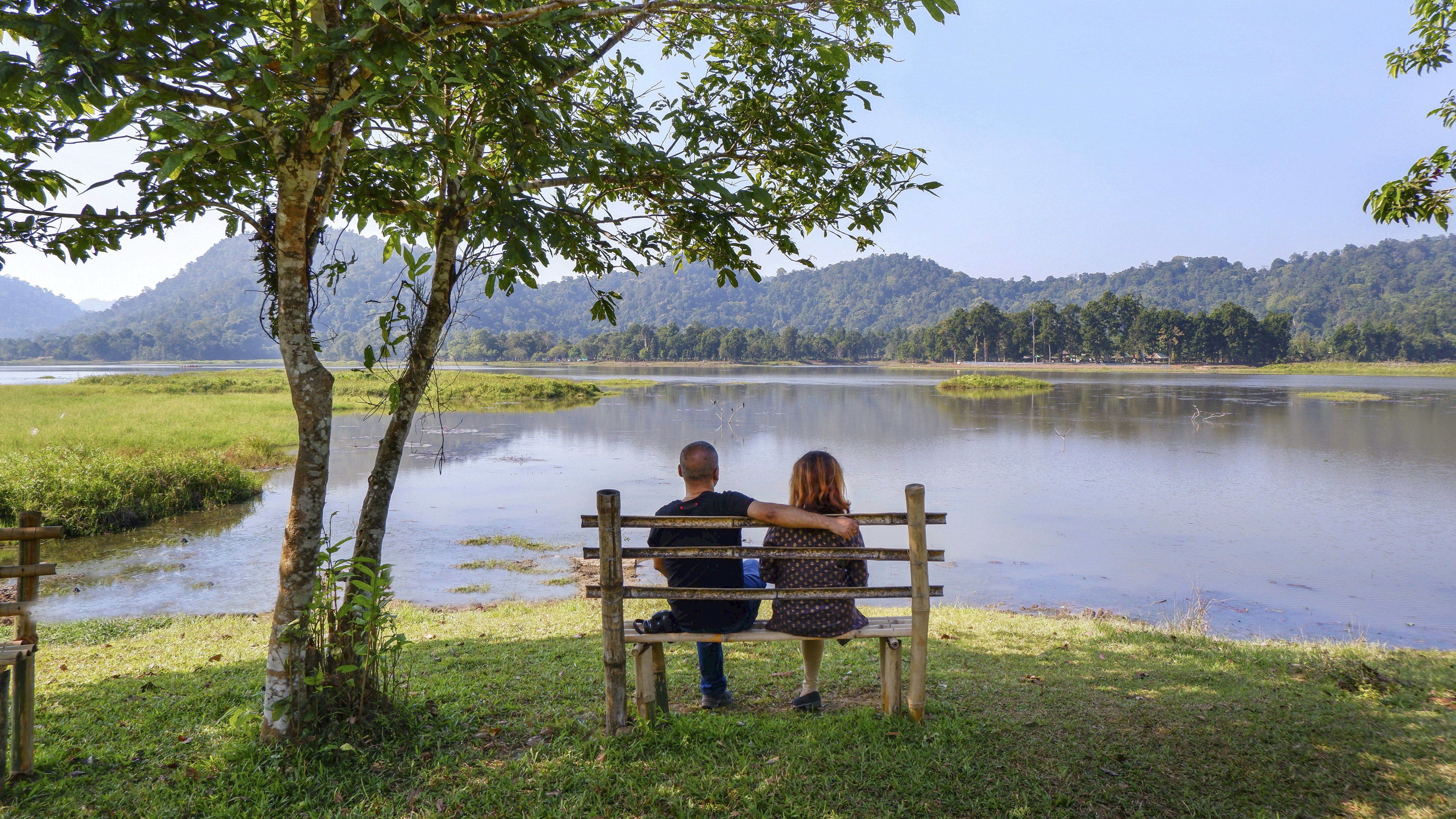 Deux personnes assises sur un banc surplombant un lac photo – Photo Lac ...