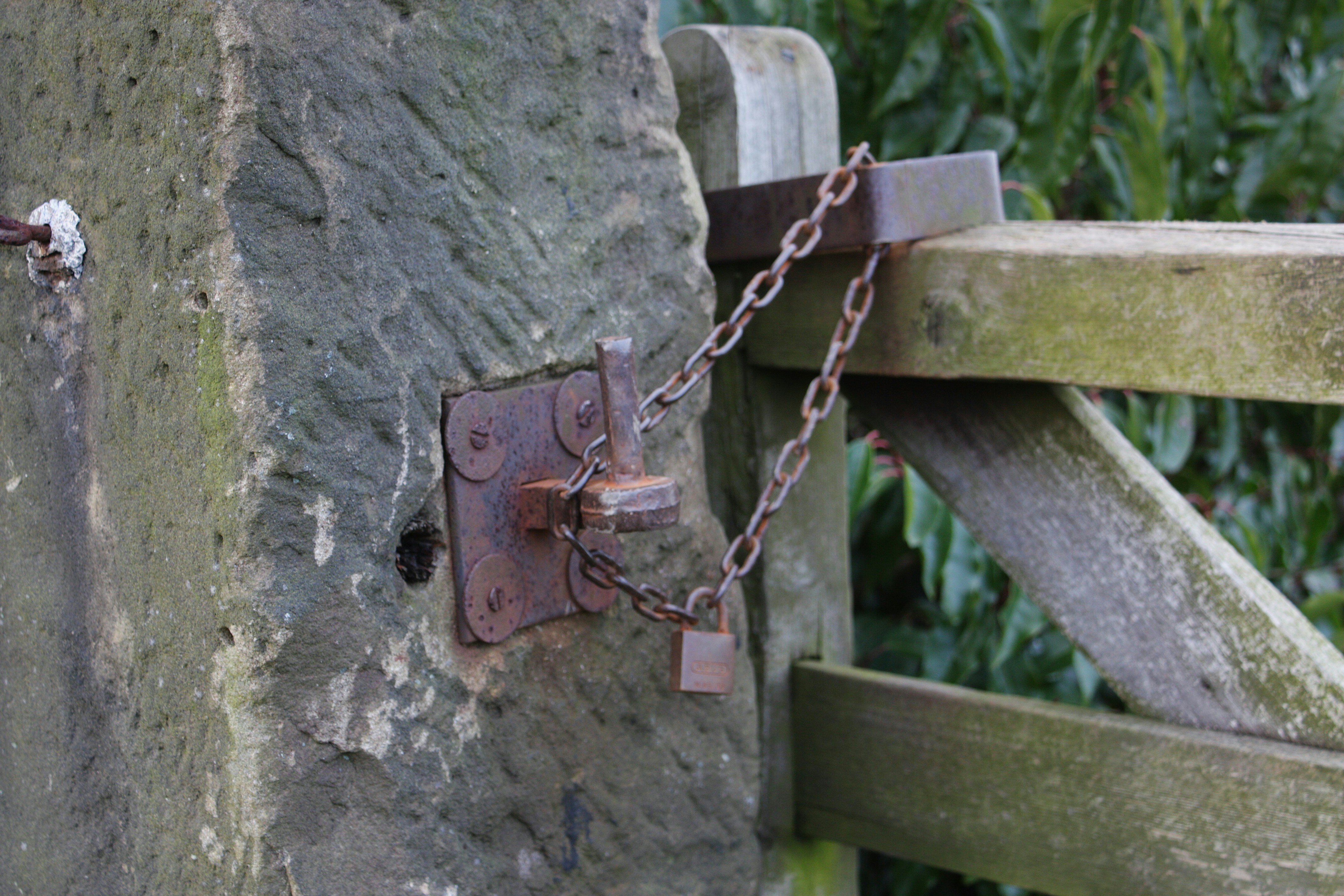 Rust and Chain: Close-Up of a Weathered Padlock Securing a Stone Gate