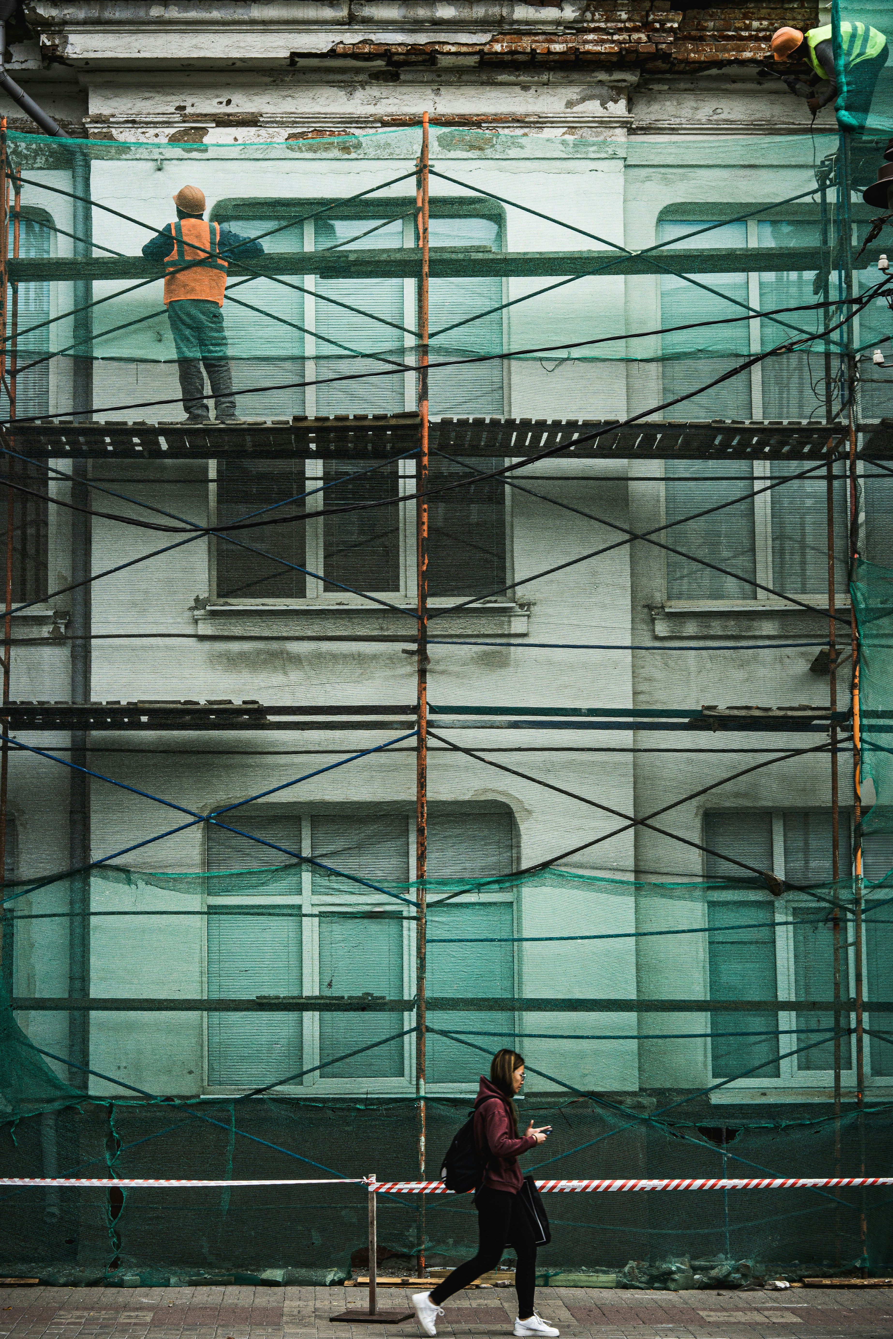 A woman walking past a tall building with scaffolding photo – Free ...