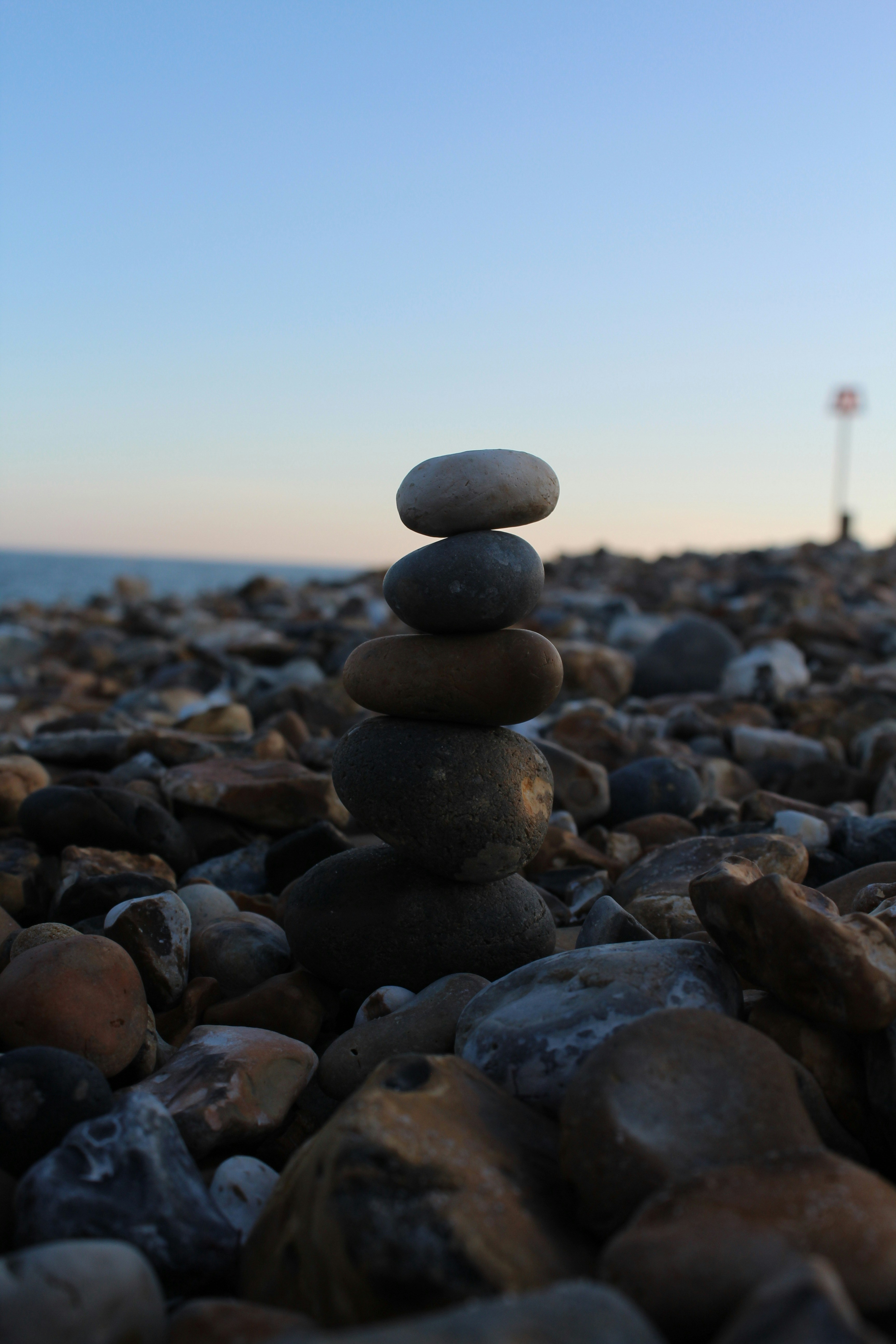 A stack of rocks on a rocky beach as the sun starts to set behind