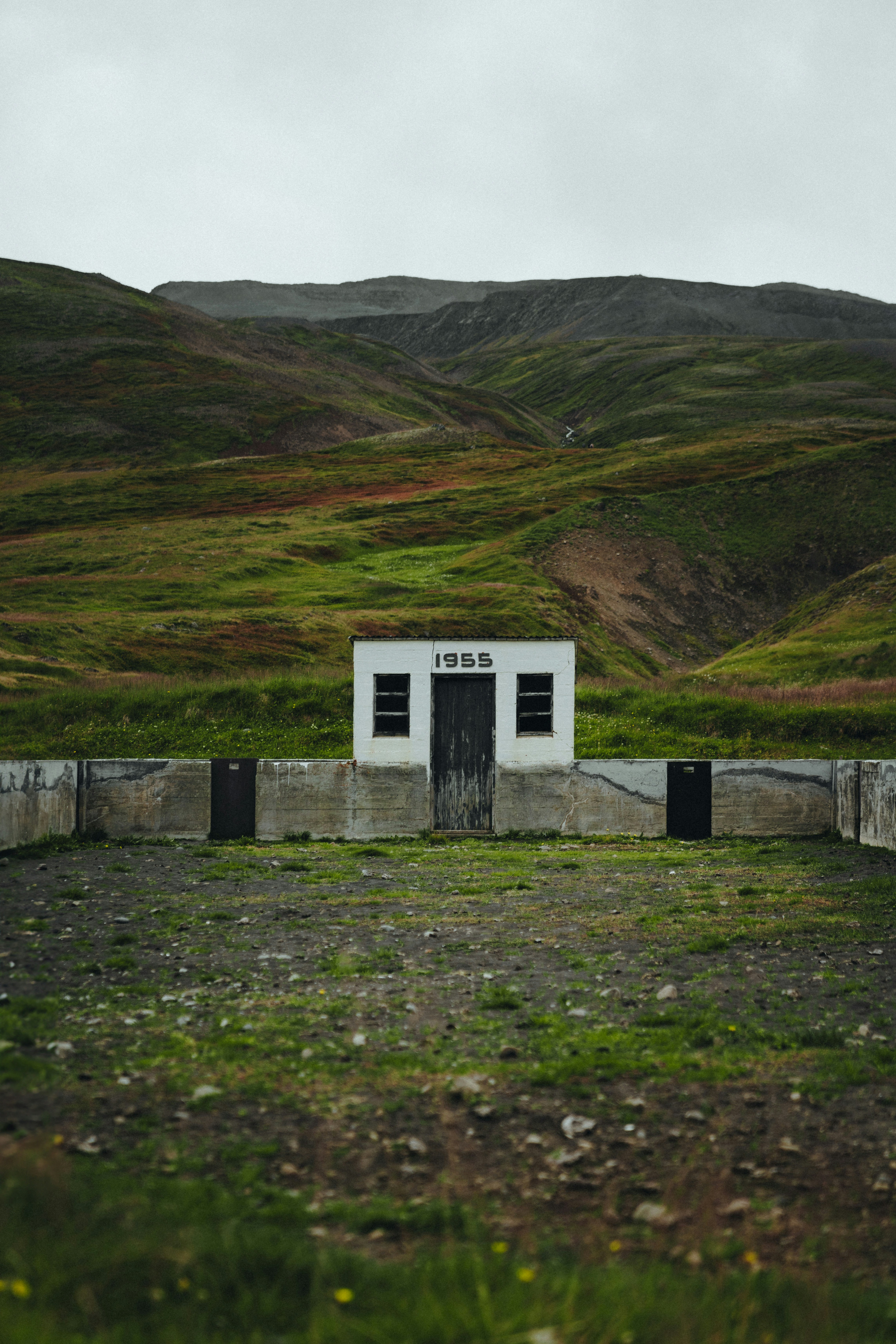 A small white building sitting on top of a lush green hillside photo ...
