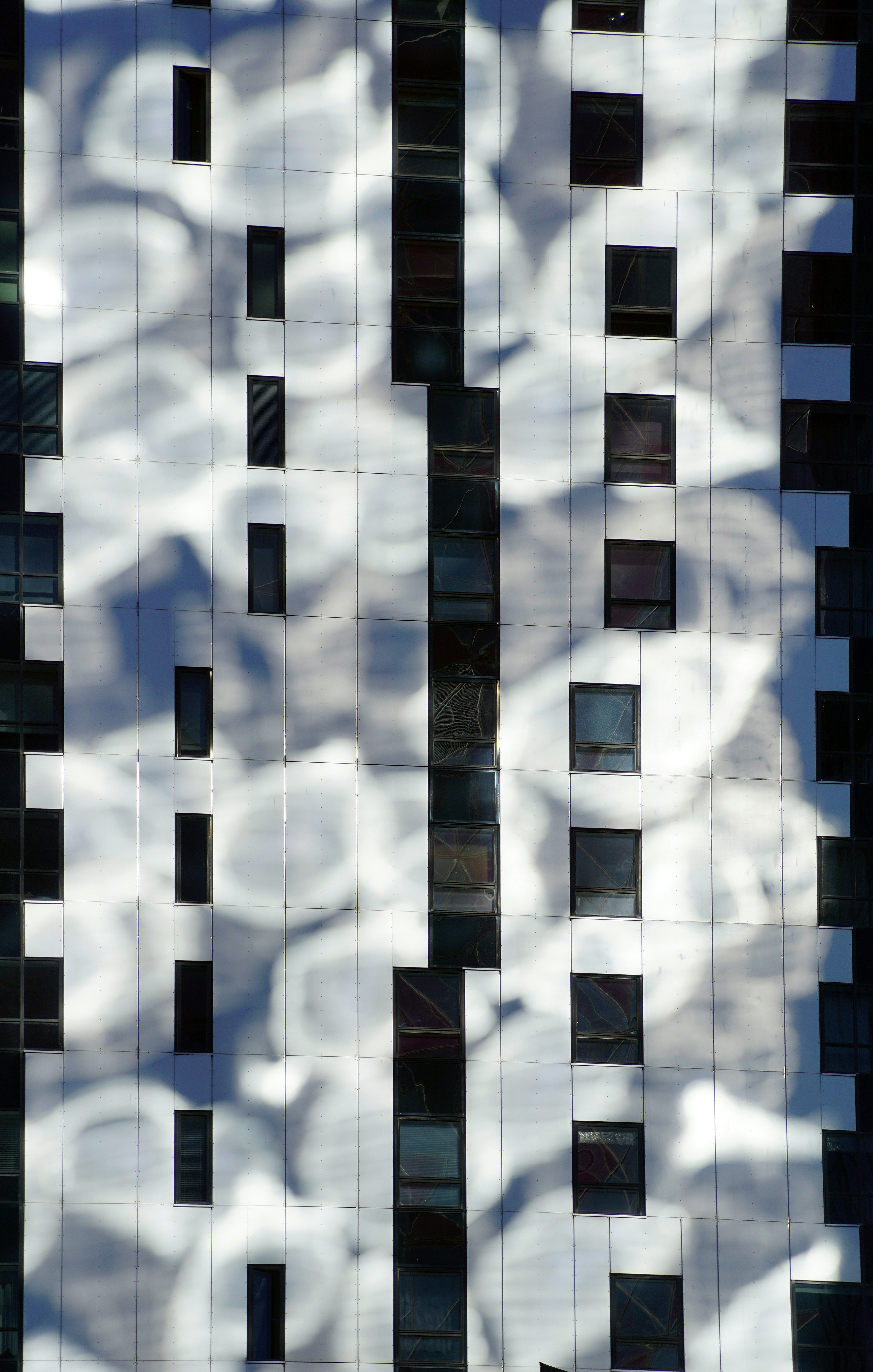 Reflections of the sun on the side of a modern white building with dark windows in Tallinn, Estonia.