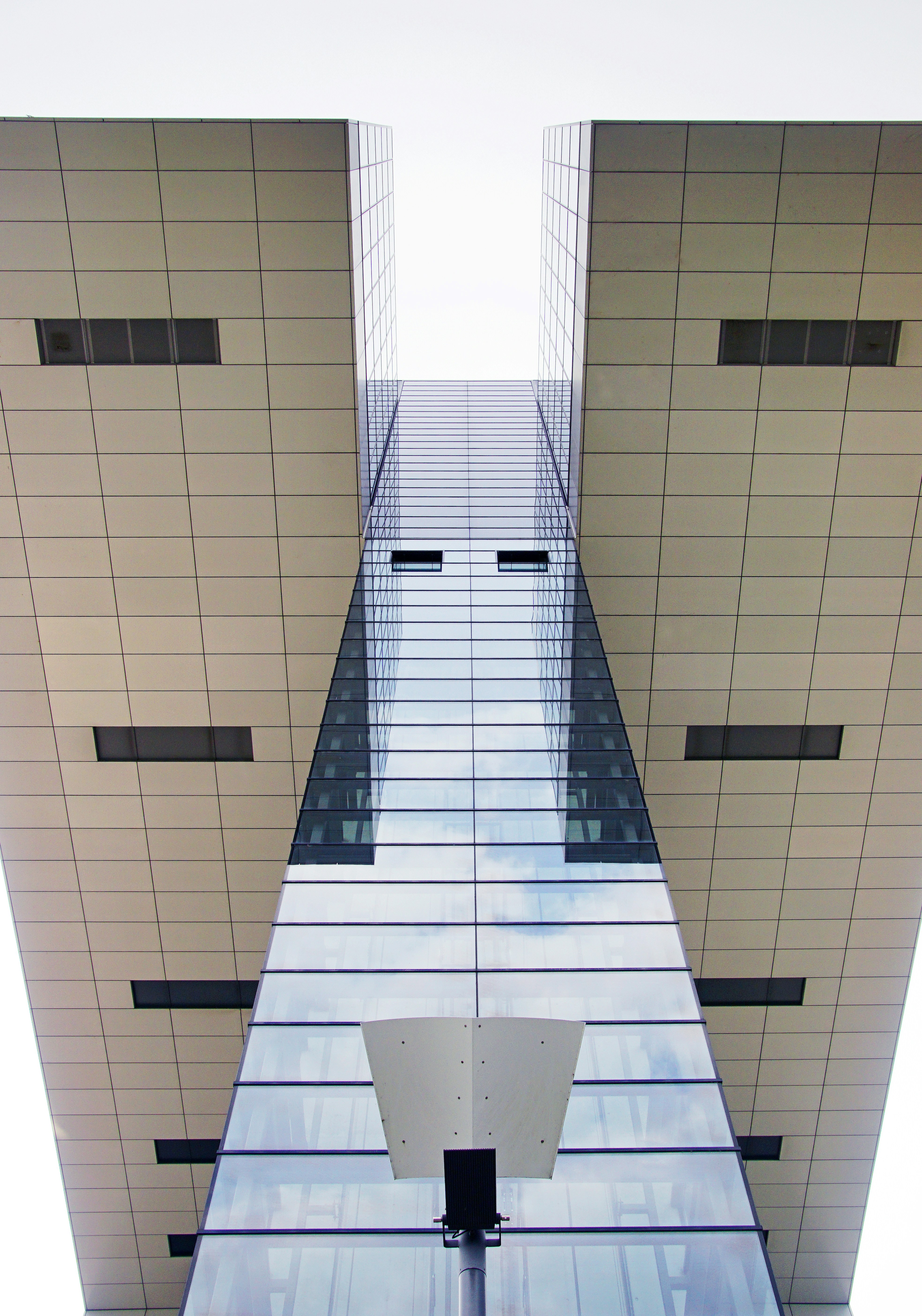 A striking view of a contemporary building showcasing a glass facade and unique structural design, emphasizing symmetry and modernity.