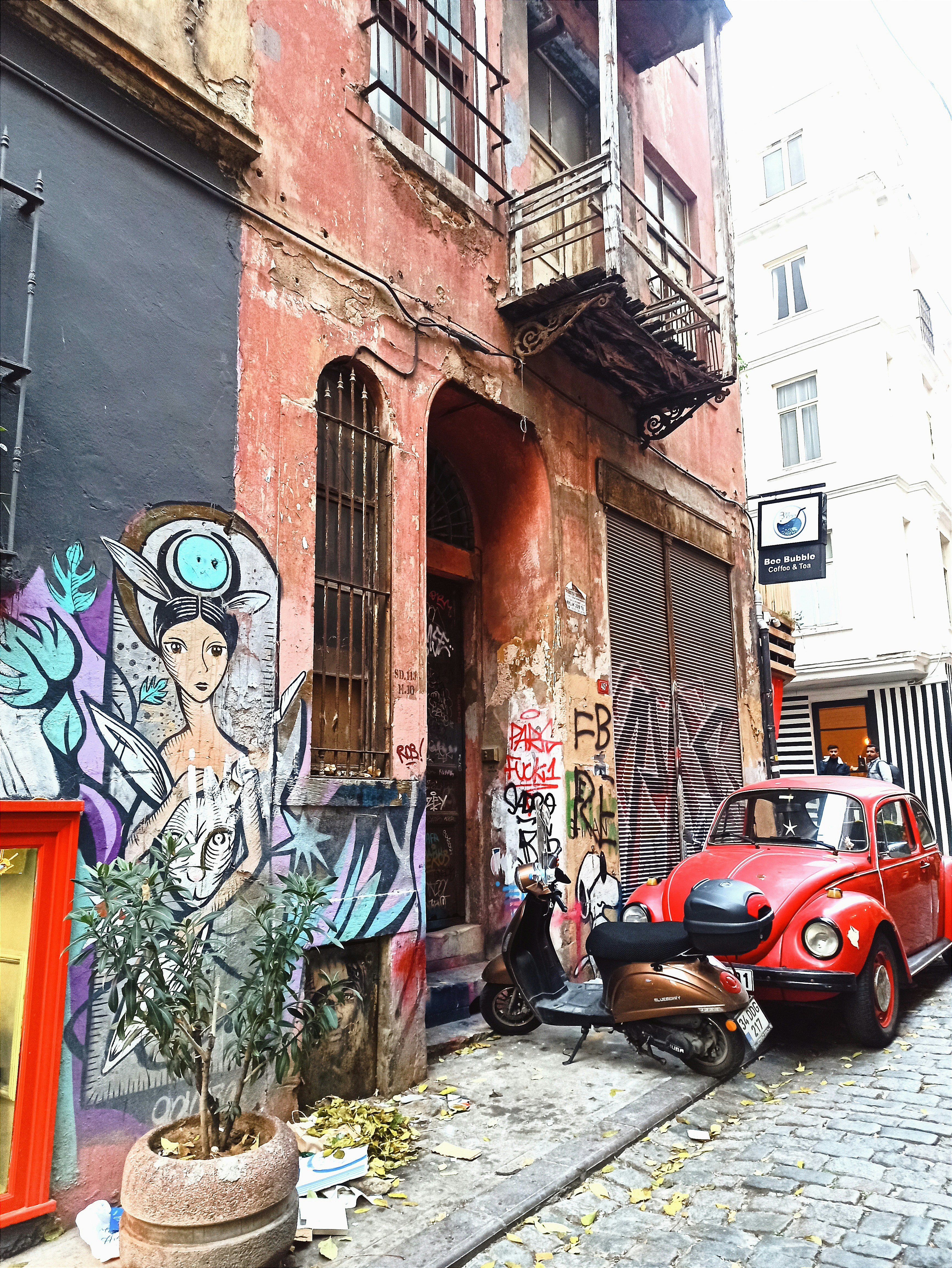 Red Scooter Alleyway: Graffiti, Vintage Car, and Sunlit Facade