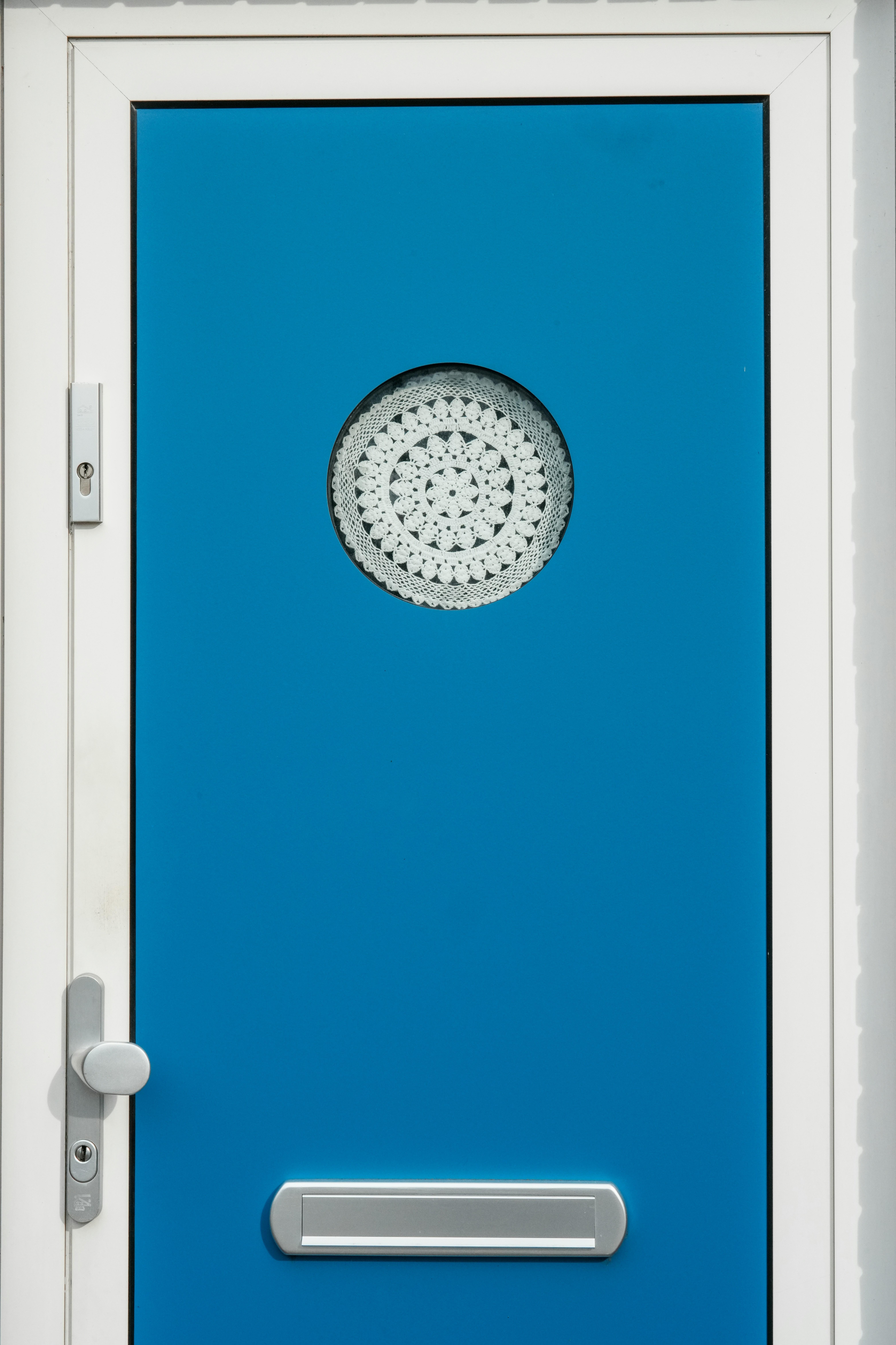 Round hole window in blue door with crochet doily mandala decor