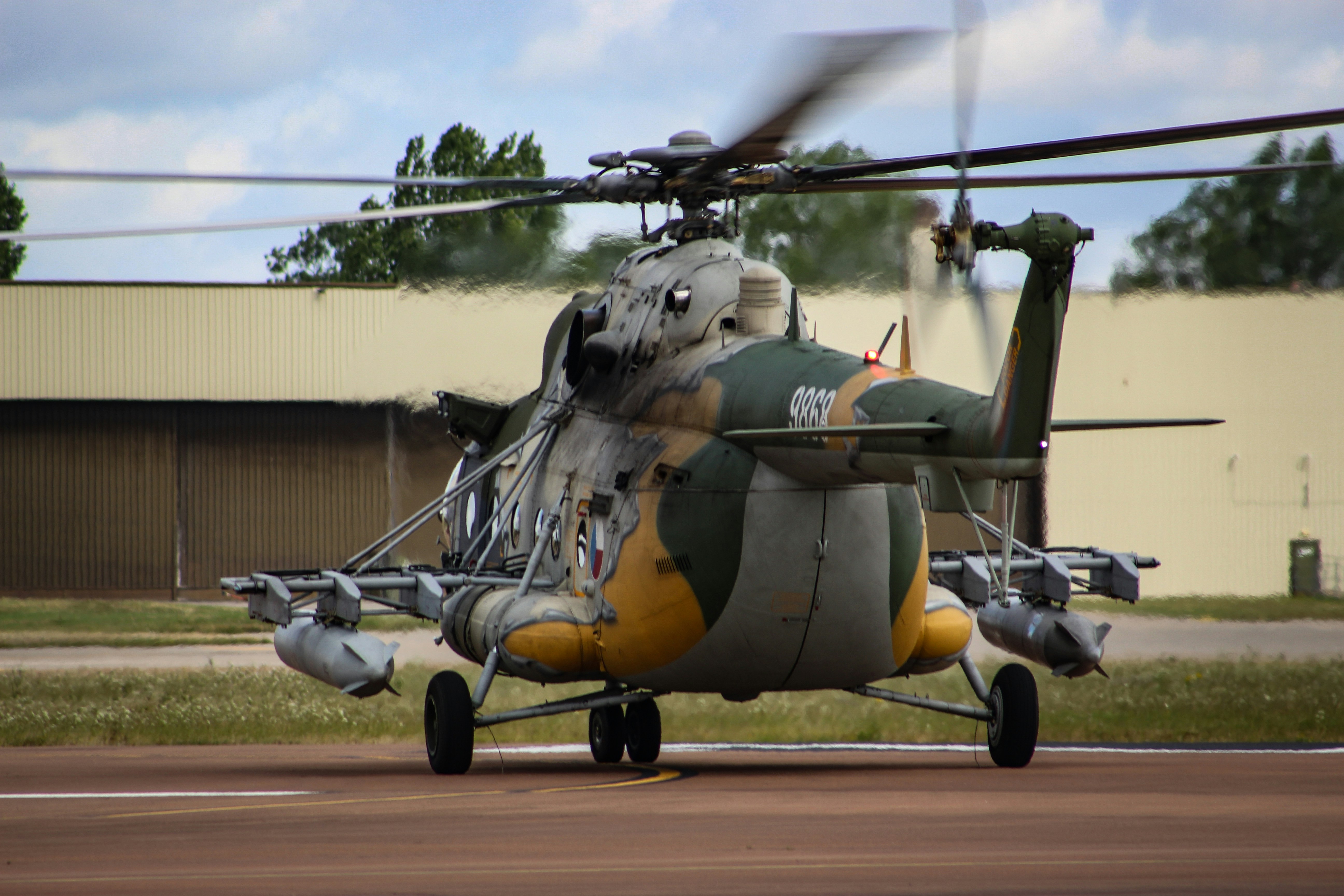 Front-Facing Camouflage Helicopter on an Empty Airstrip with Rotor Blur