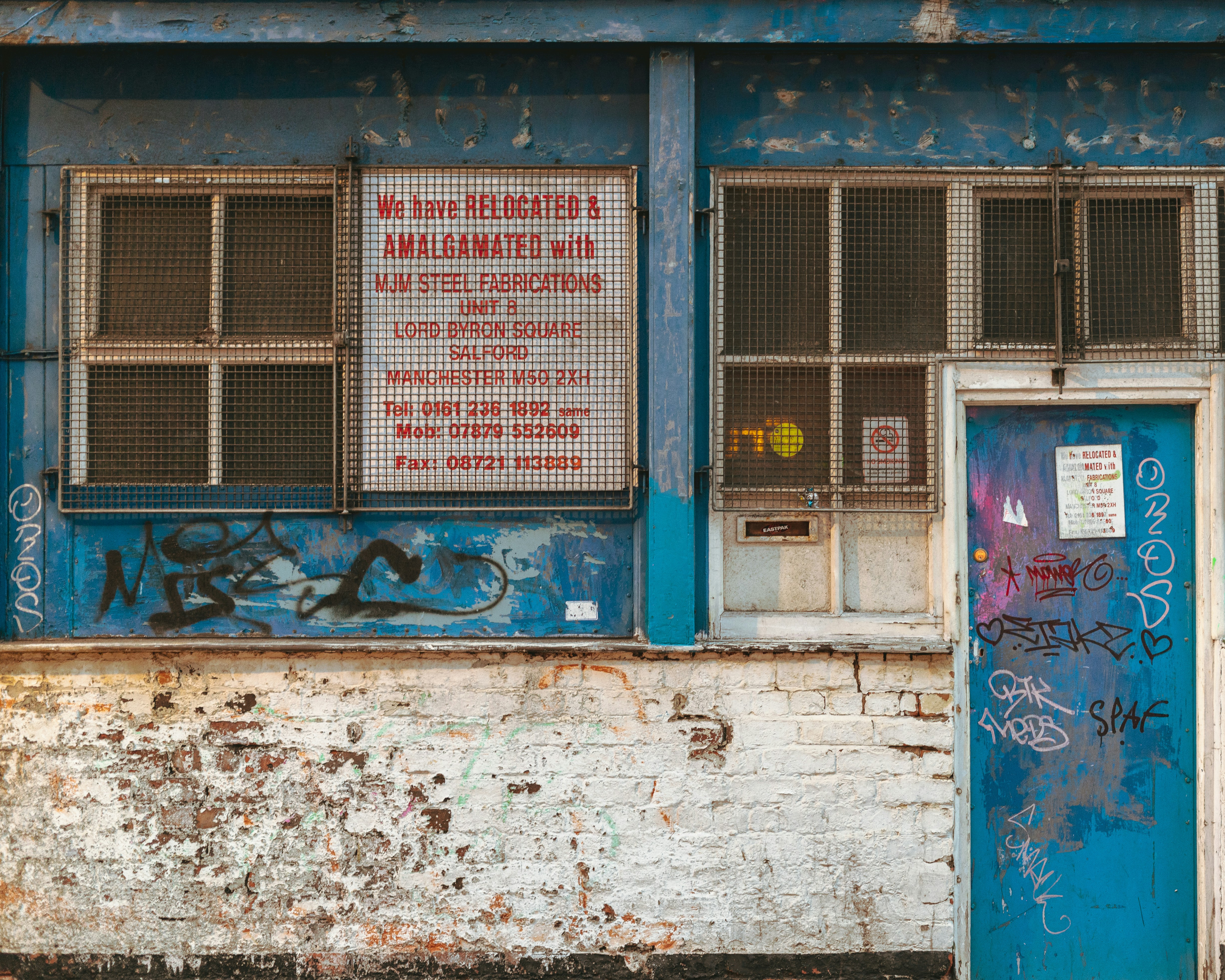 Blue storefront with weathered graffiti and worn doorways