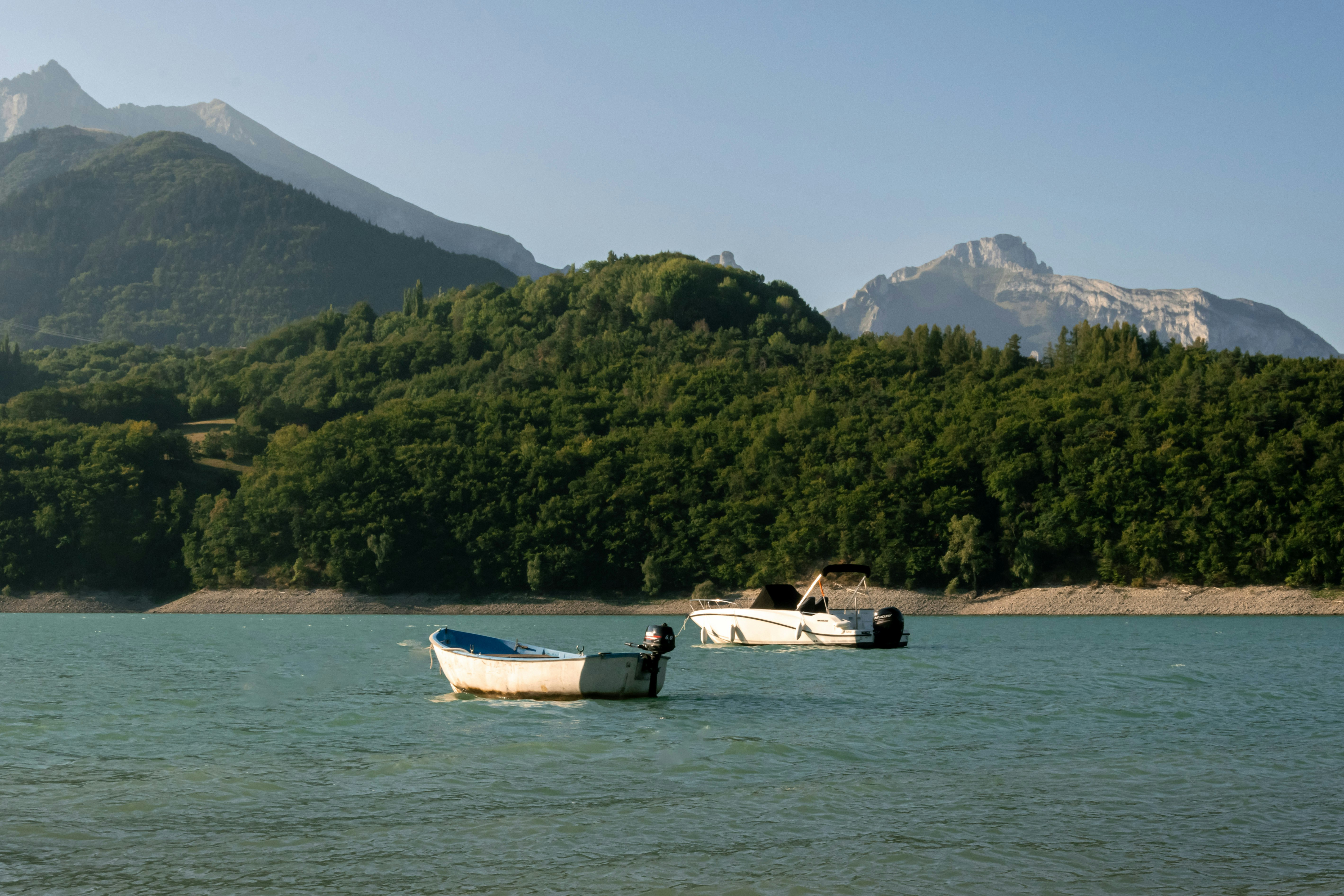 A couple of boats floating on top of a lake photo – Free Lac du sautet ...