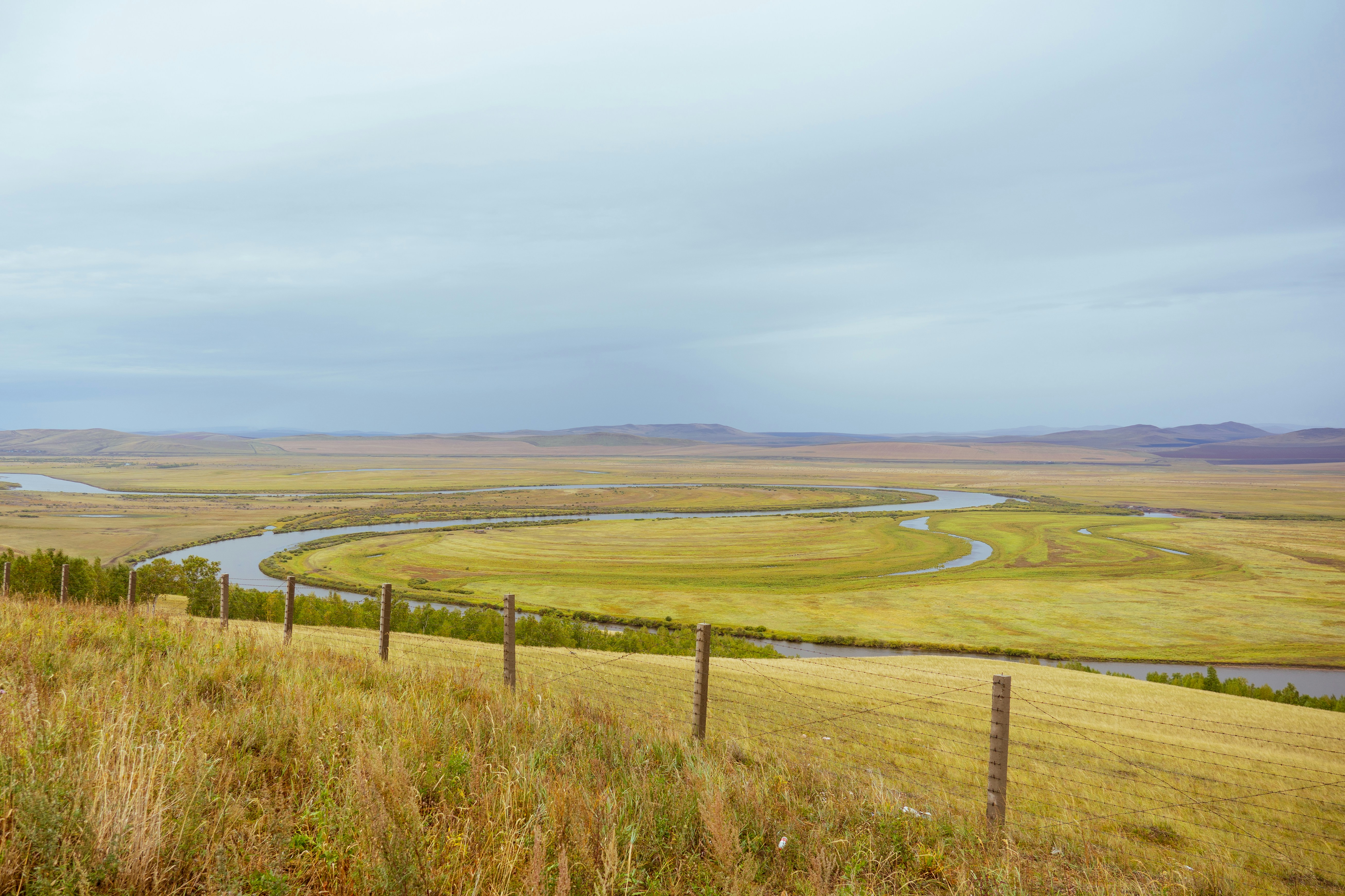 A grassy field with a river running through it photo – Free Inner ...