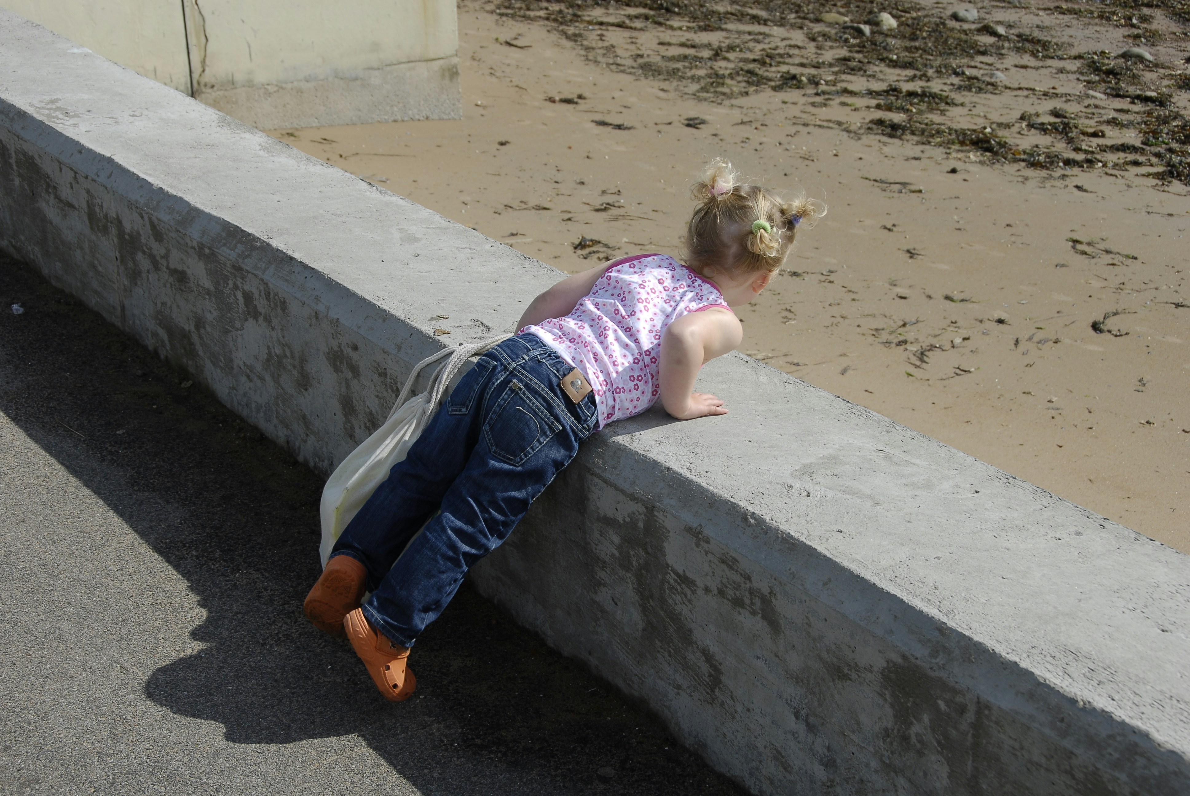 Edge of the Sea: a young girl leans along a sunlit seawall