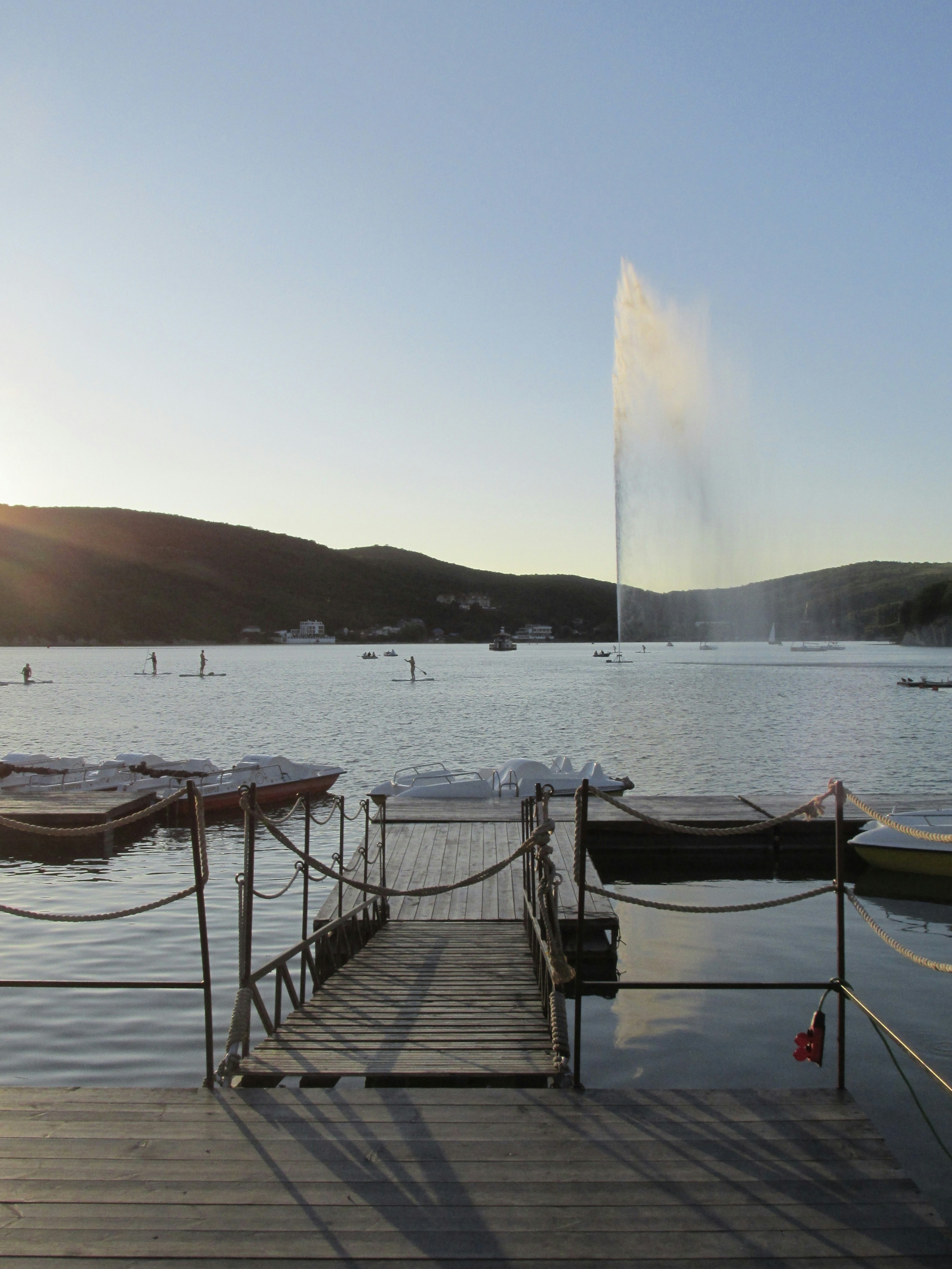A wooden dock with a water spout in the distance photo – Free Water ...