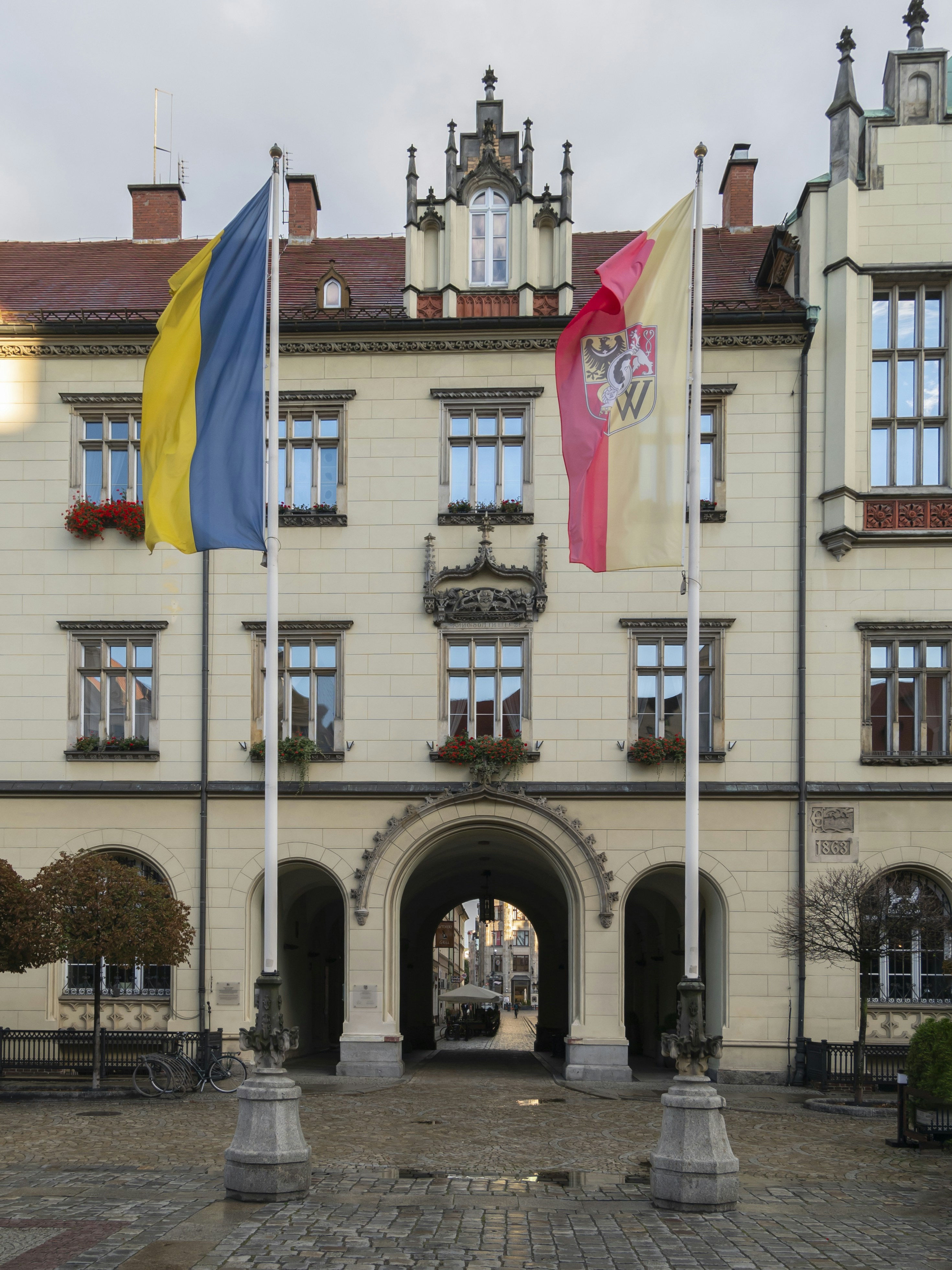 Flagpoles with the flags of Ukraine and Wroclaw in front of the New City Hall on the market square in the old town after the rain