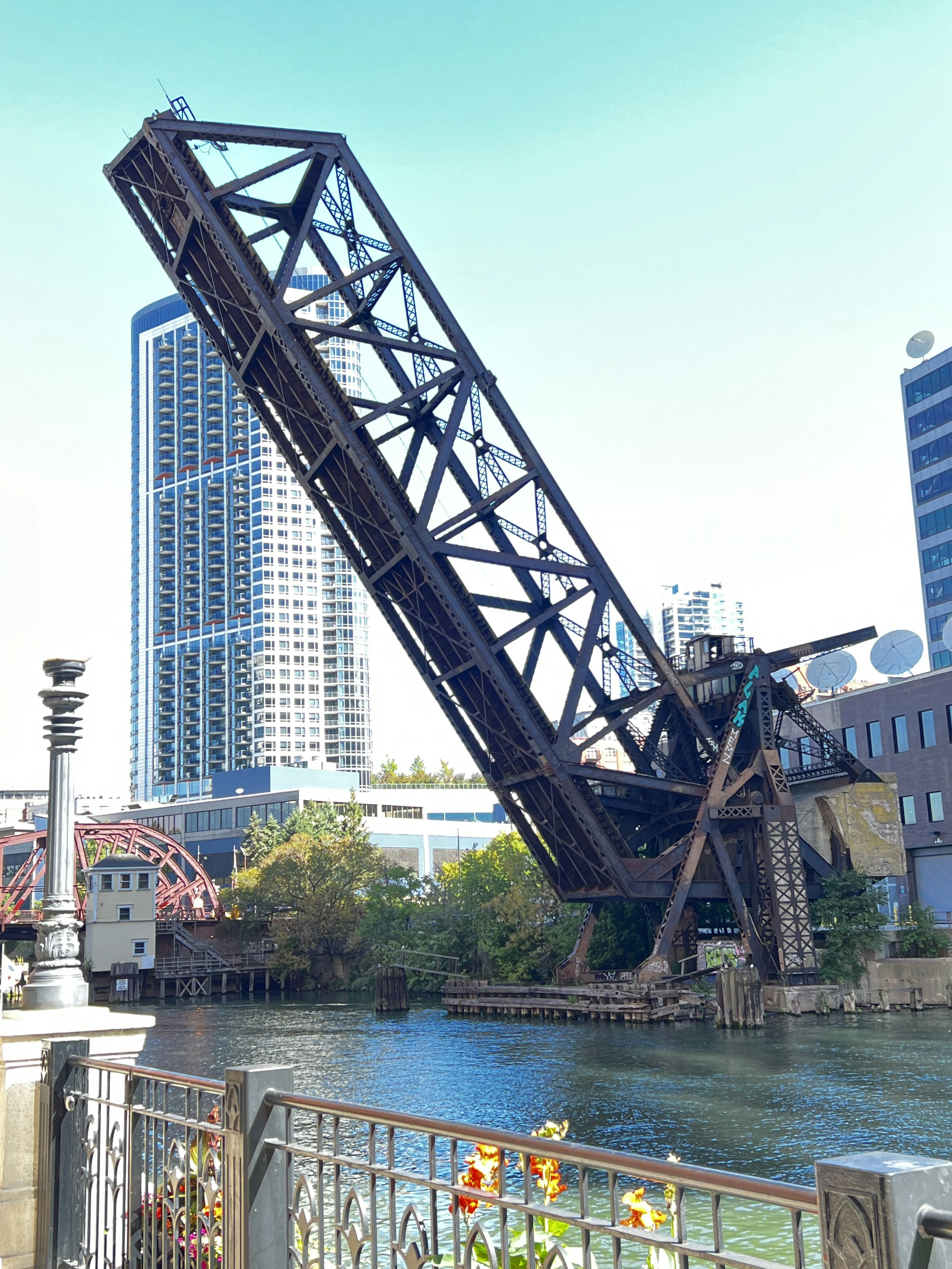 A large metal bridge over a river next to tall buildings photo – Free ...