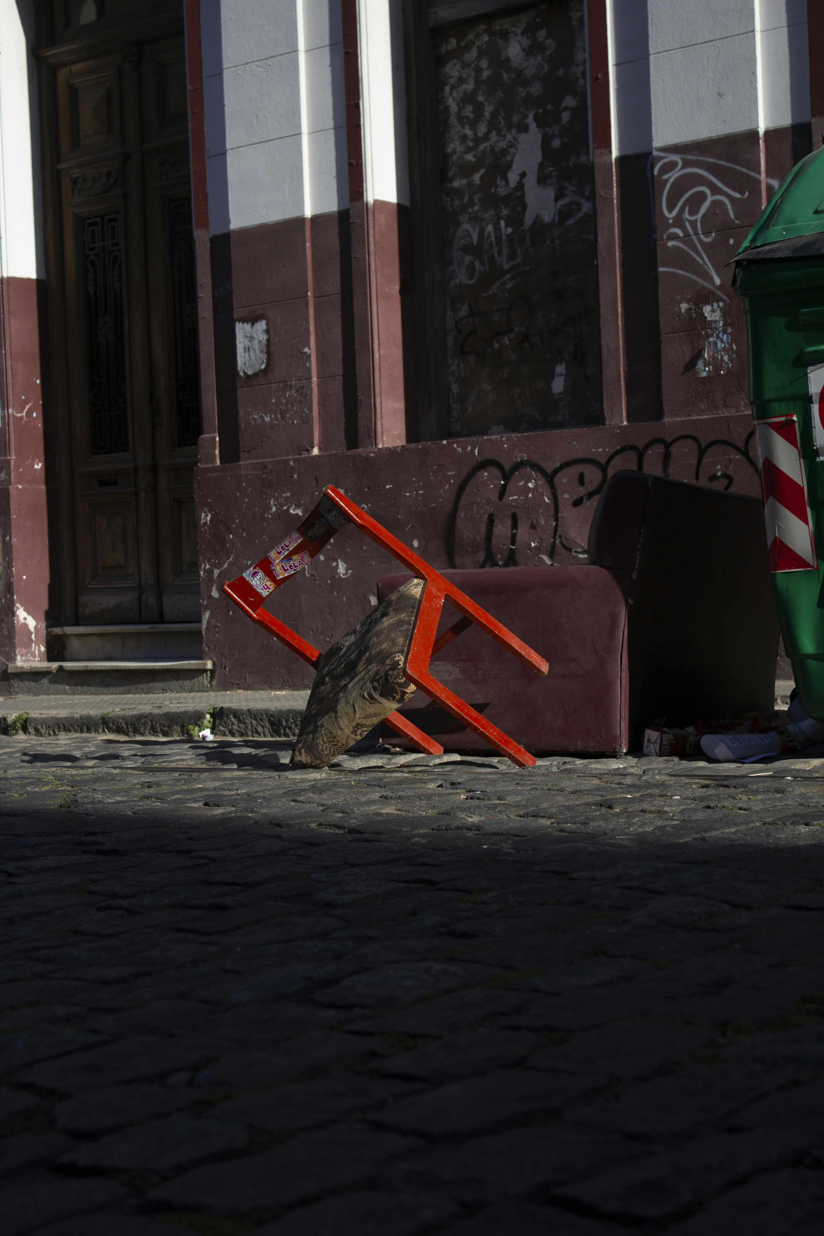 Leaned Orange Chair Frame in a Graffitied Alley