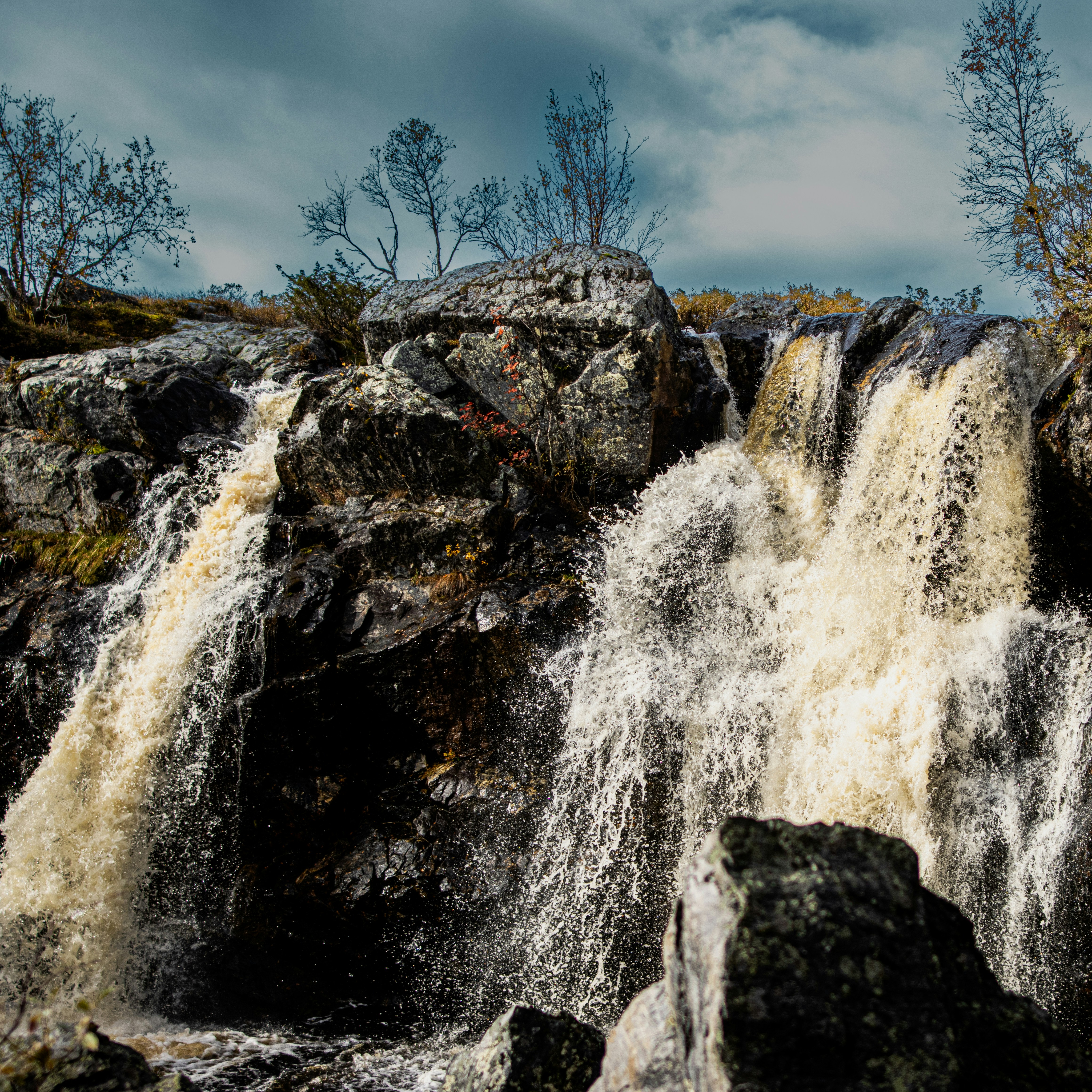 Granite Cascade: Water Surges Over Dark Rock Beneath an Open Sky