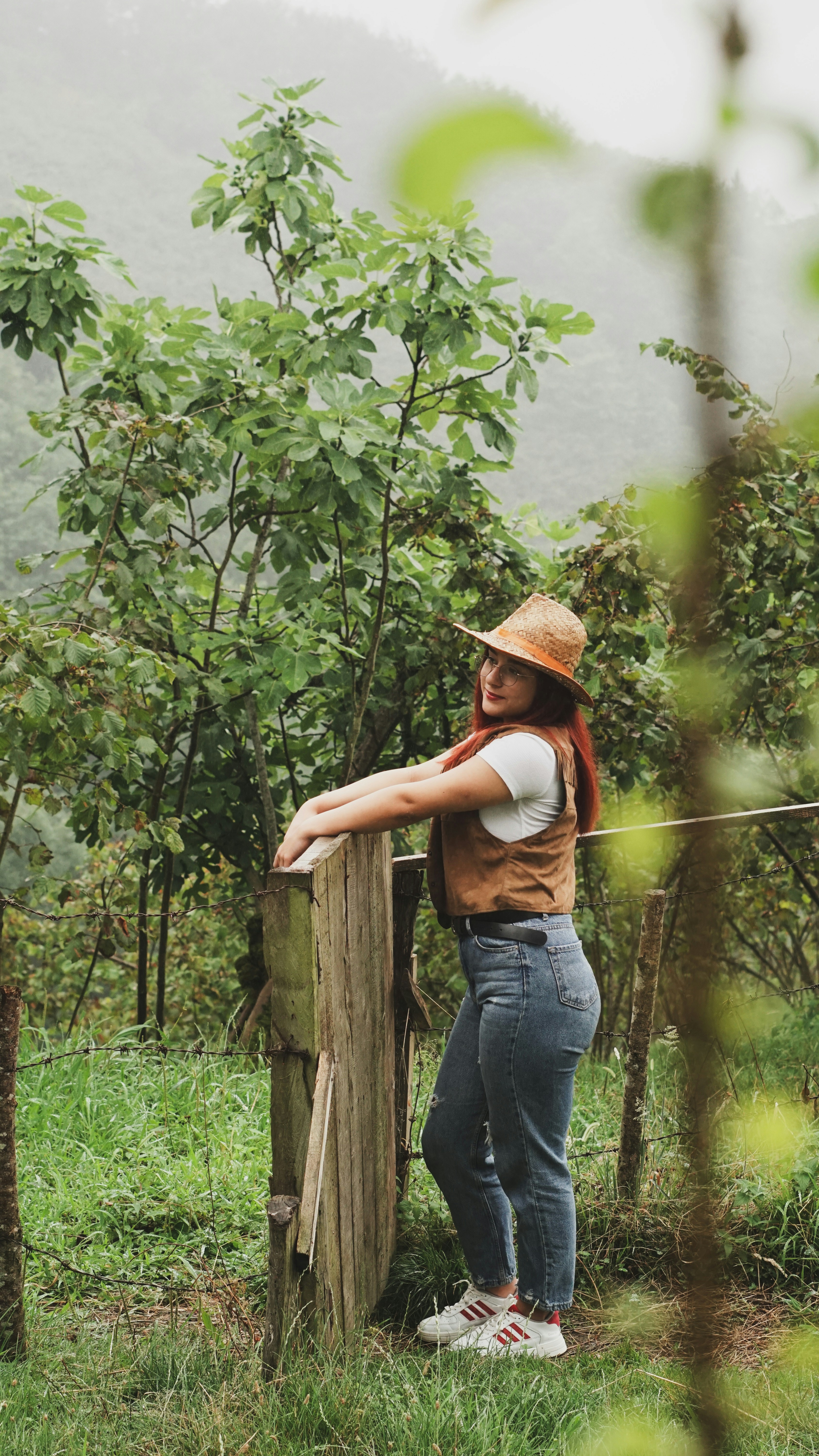 A woman leaning on a wooden post in a field photo – Free Woman Image on ...