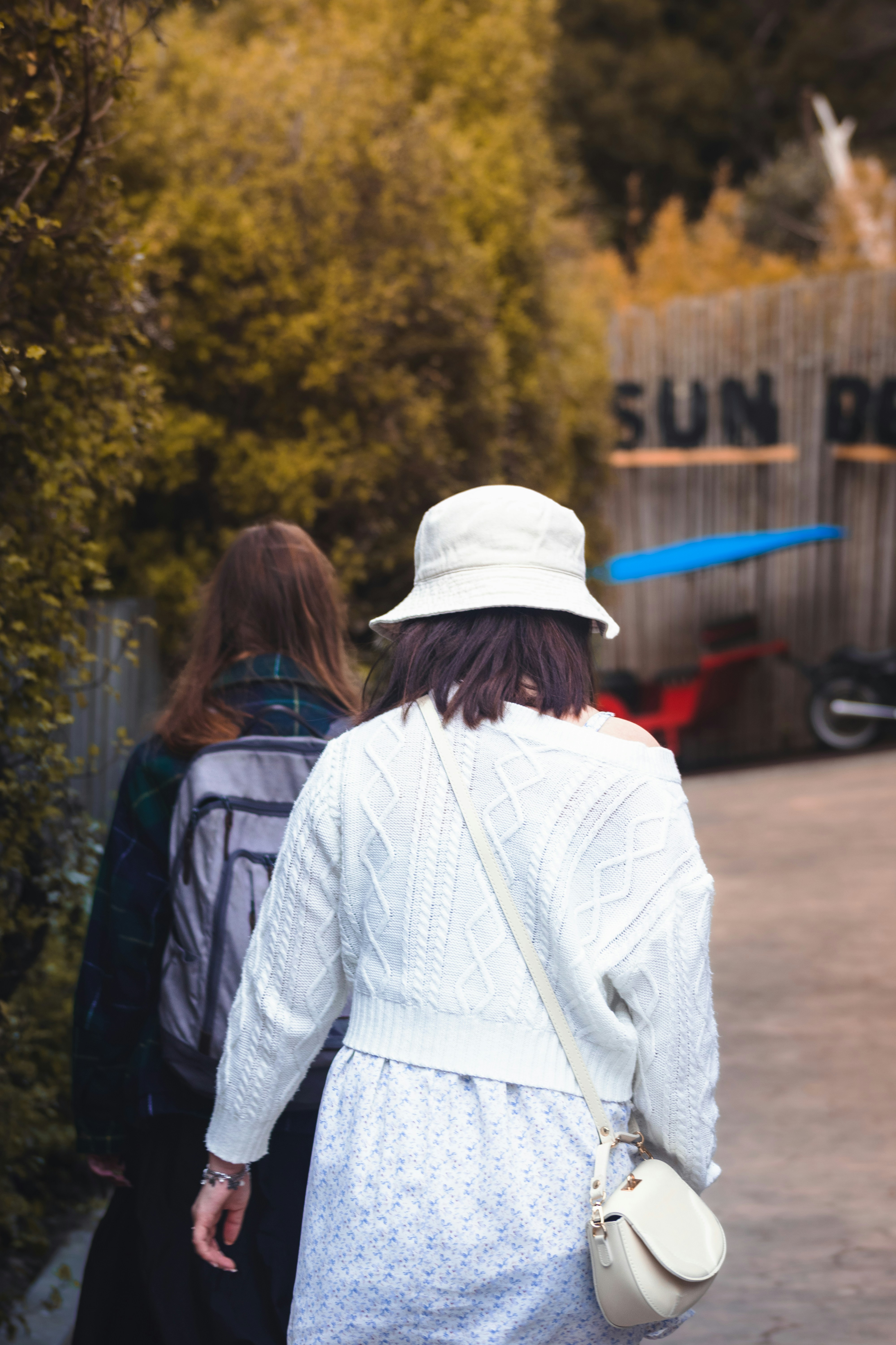 Autumn Step: White-Knit Figure Leads a Pair Down a Sunlit Path