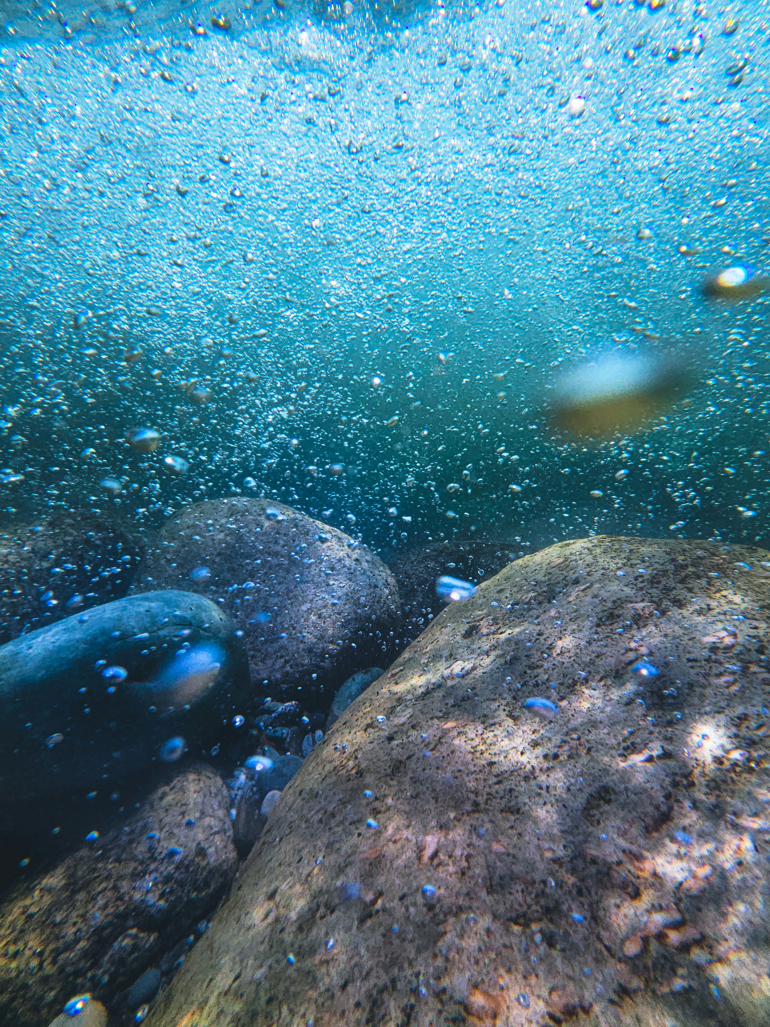 Underwater Mosaic: Boulders and Bubbles in Sunlit Turquoise