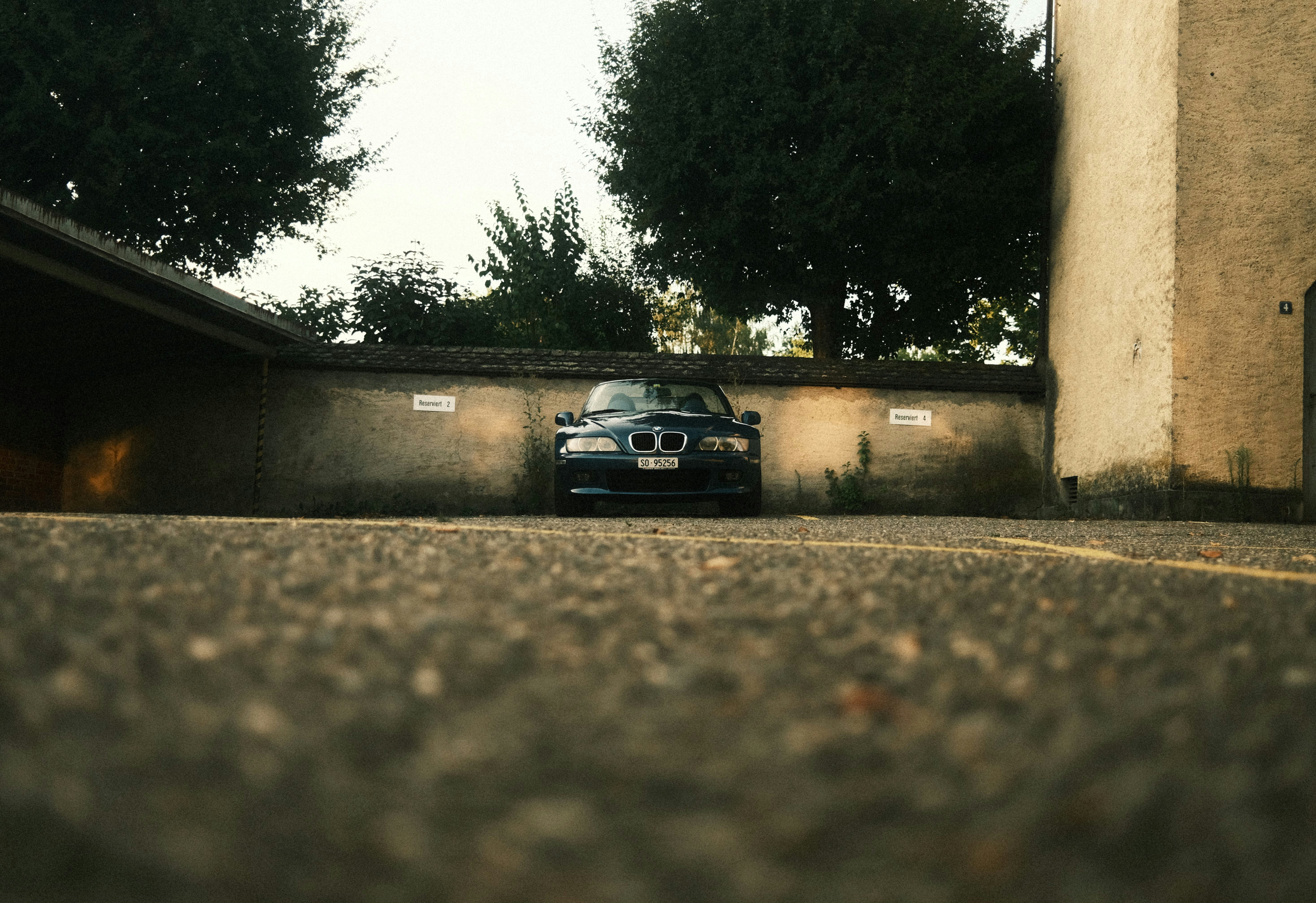 Low-Angle Quiet: BMW Resting Against a Weathered Courtyard Wall