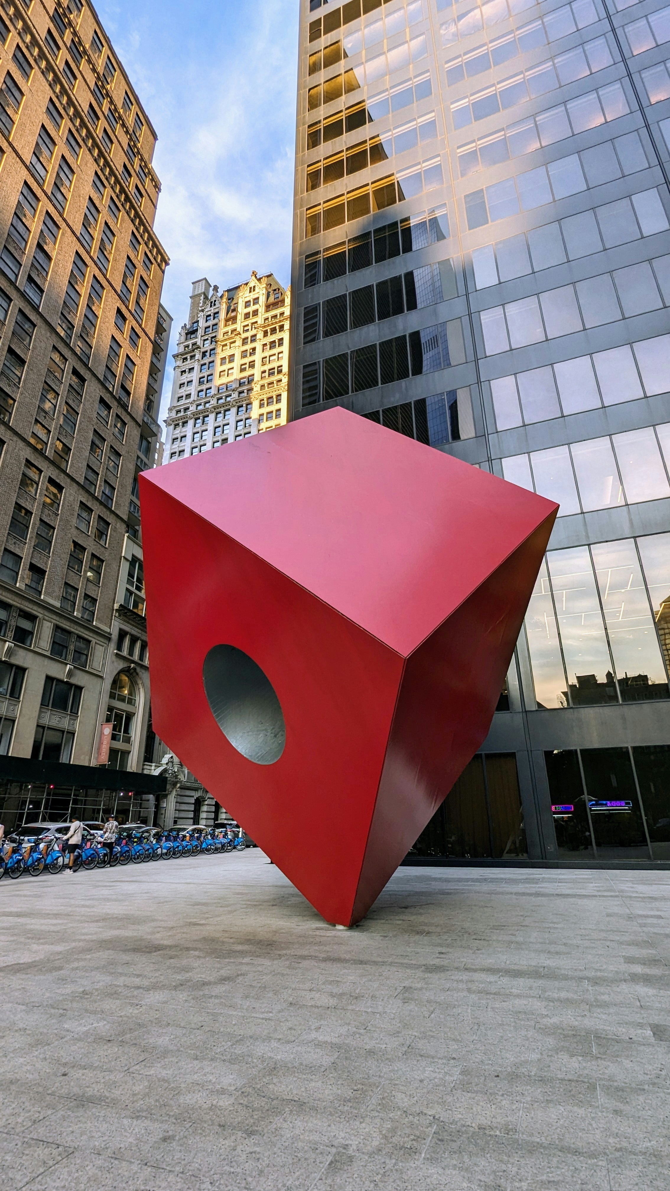 A large red object sitting in front of tall buildings photo – Free ...