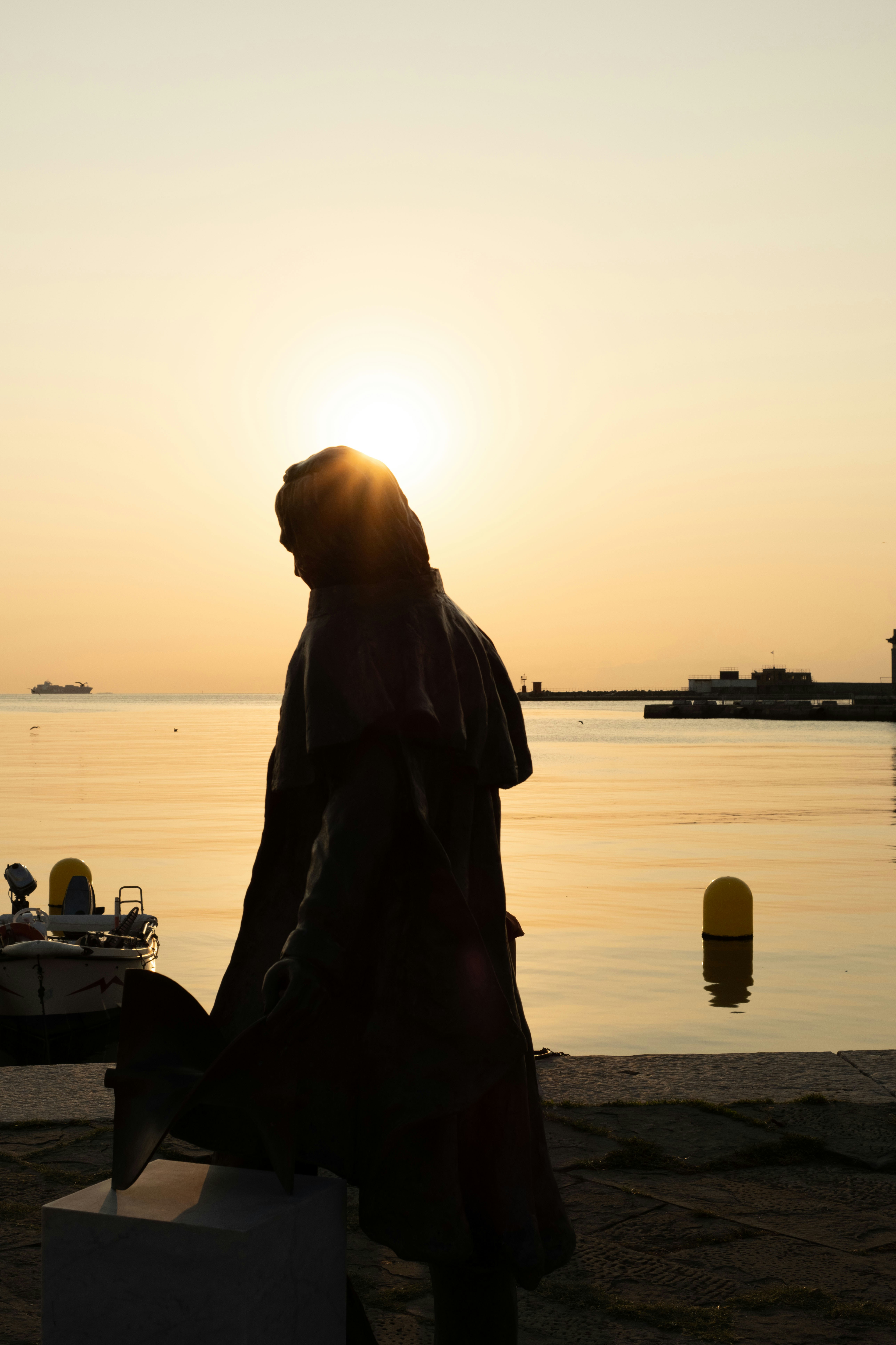 Golden Hour Sentinel: A Cloaked Silhouette at the Harbor