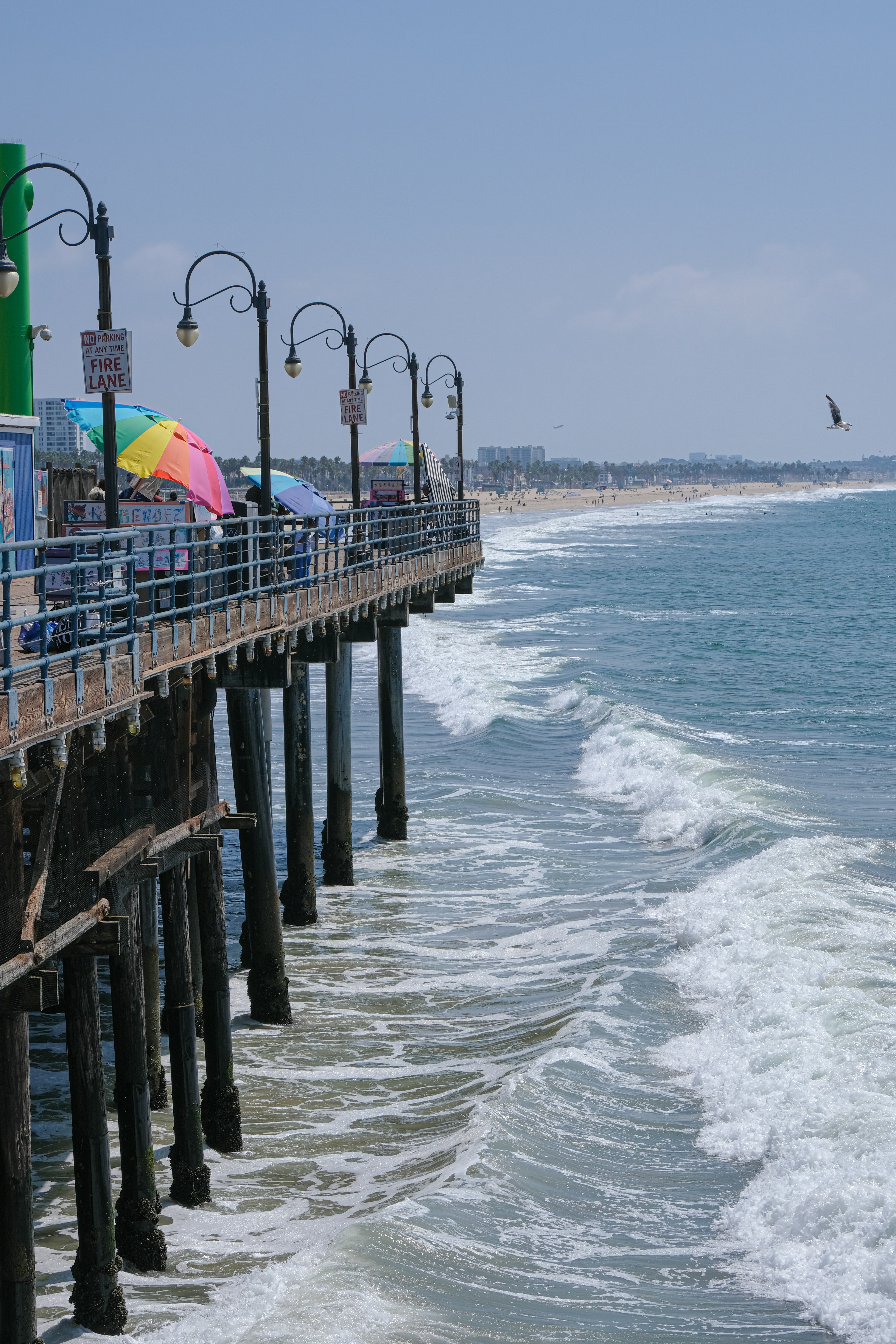 A pier with umbrellas on the beach next to the ocean photo – Free Santa ...