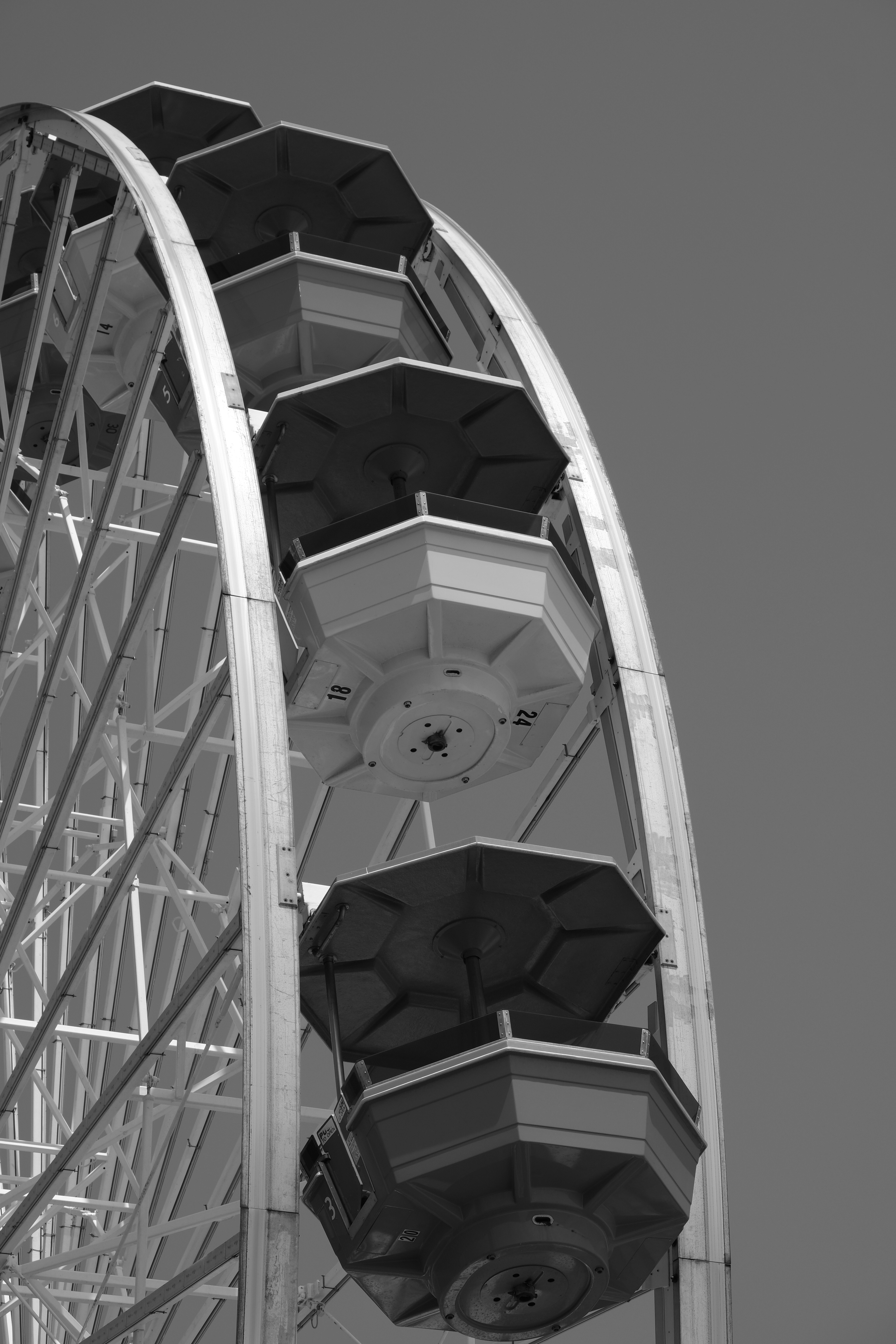 Bright Gondola Anchors a Tilted Monochrome Ferris Wheel Arc