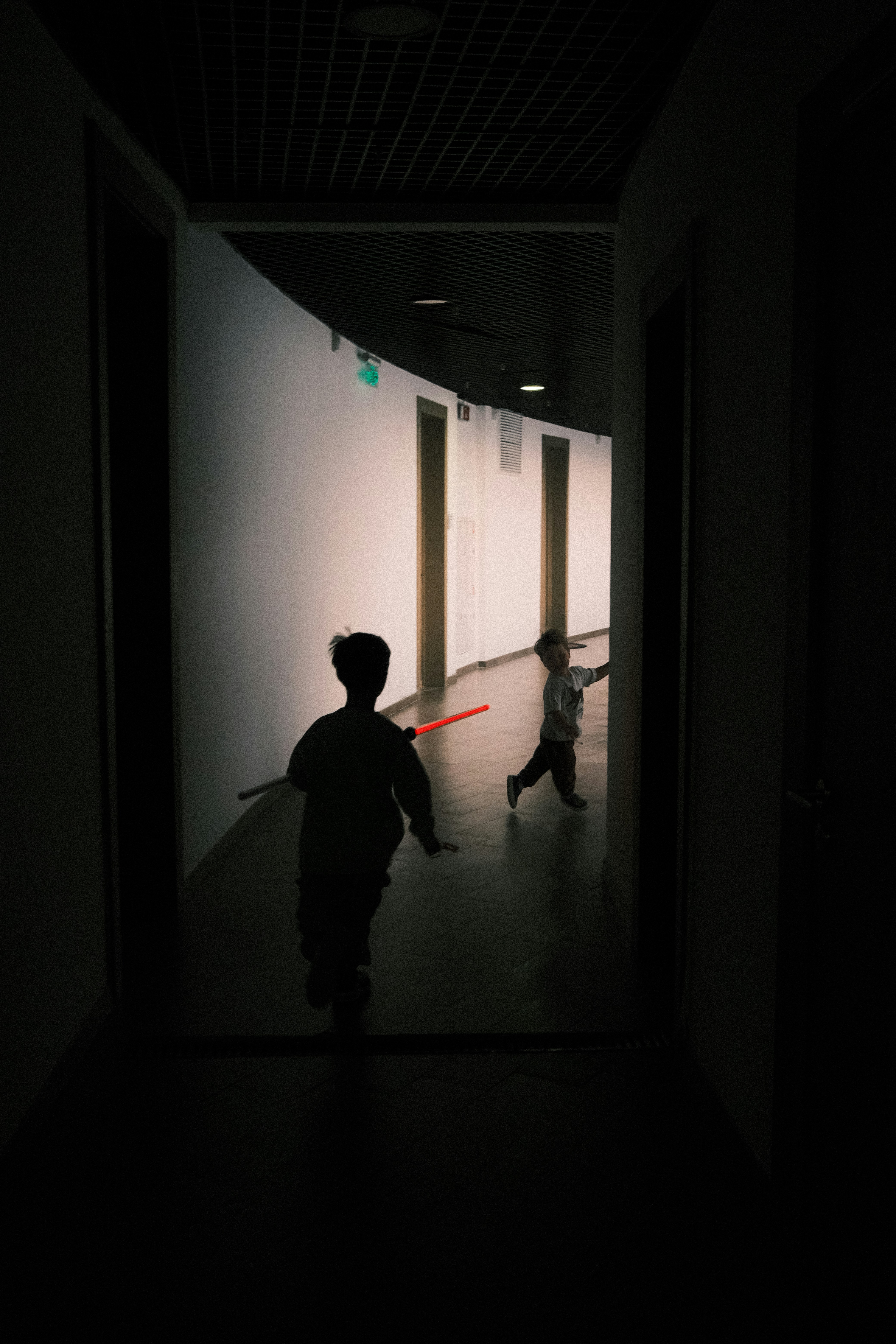 Red Glow in the Shadow Corridor: Silhouettes Dash Through a Dim Hallway