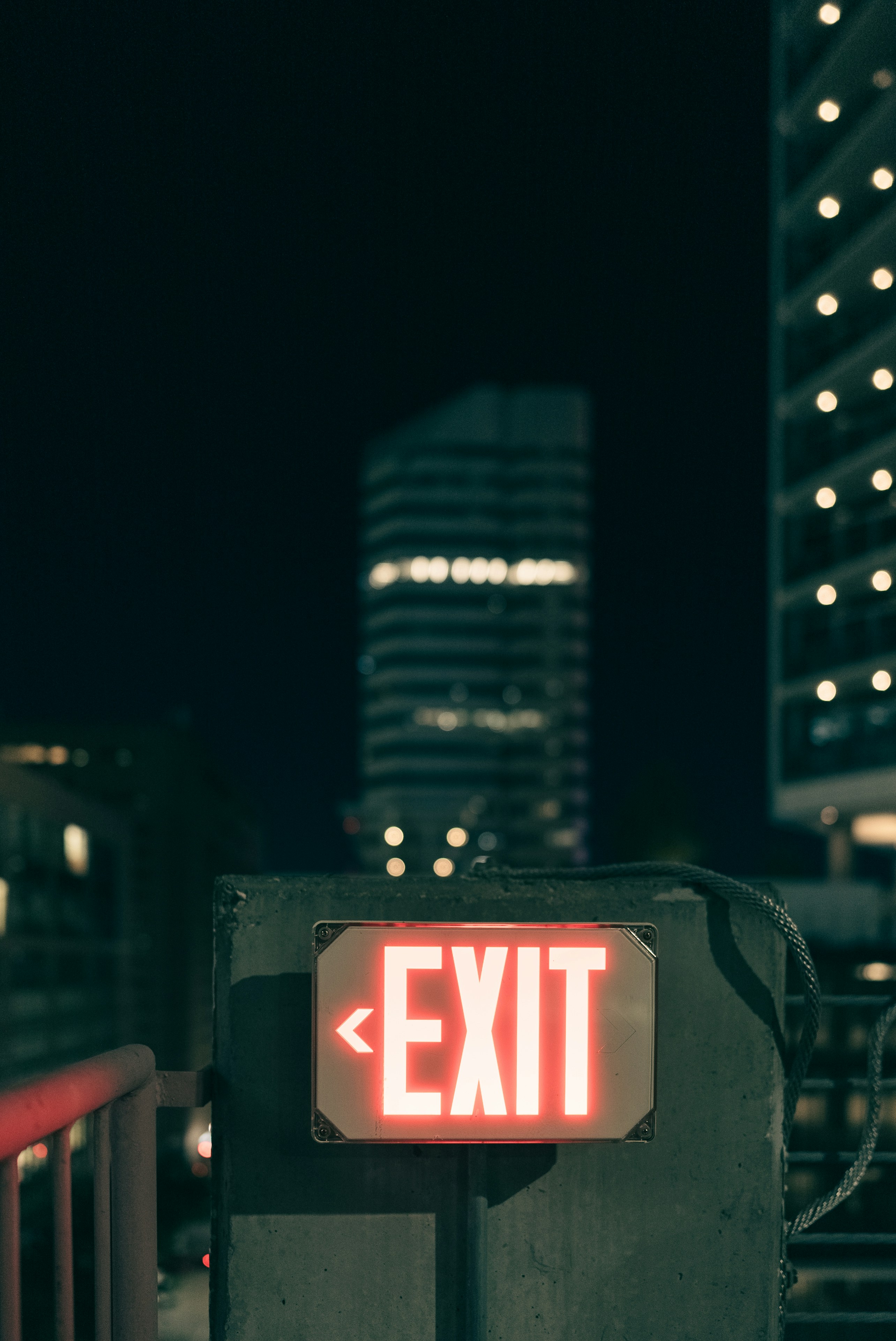 A red exit sign sitting on top of a metal pole photo – Free Image on ...