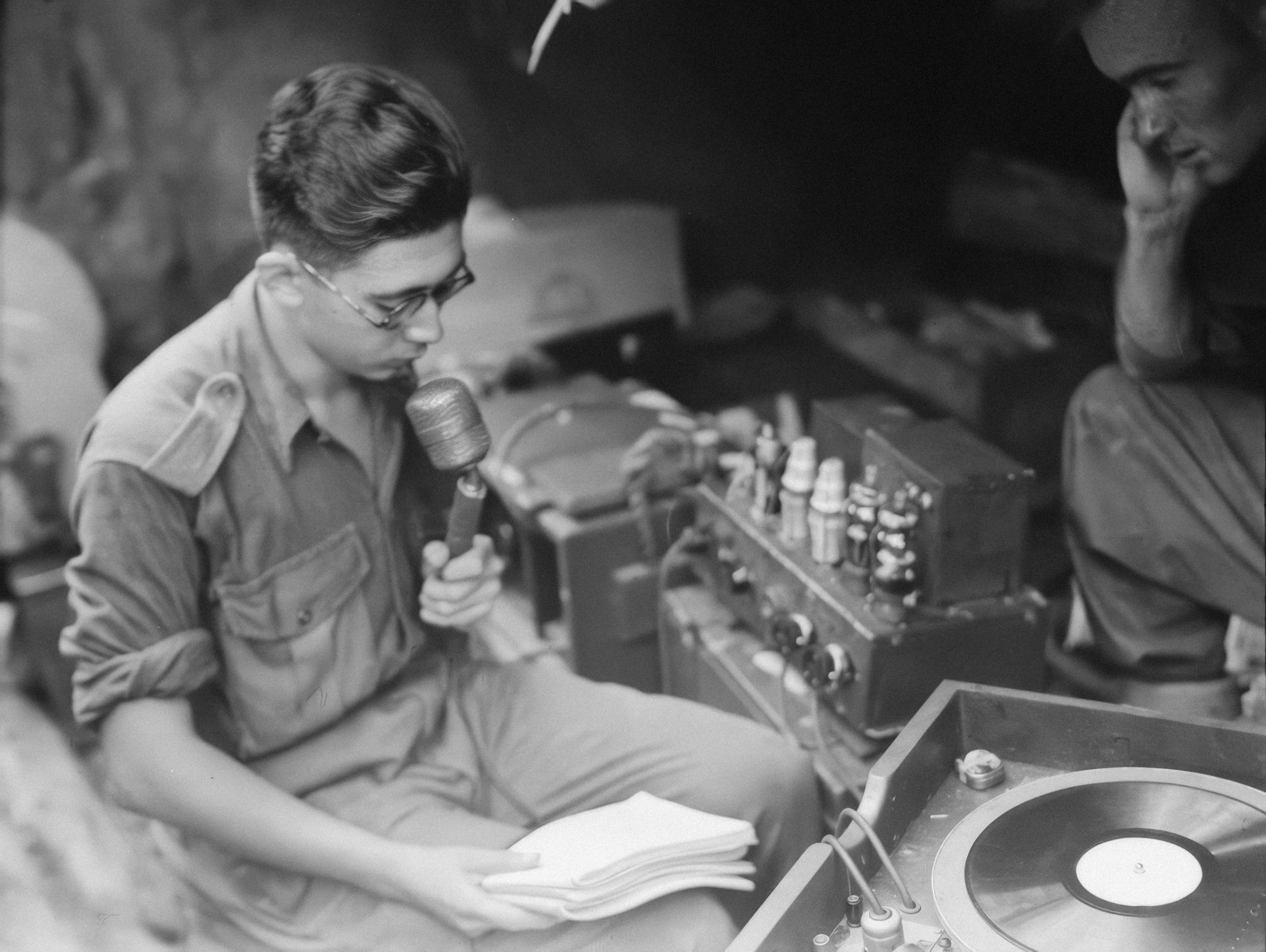 A man sitting next to a record player holding a microphone photo – Free ...