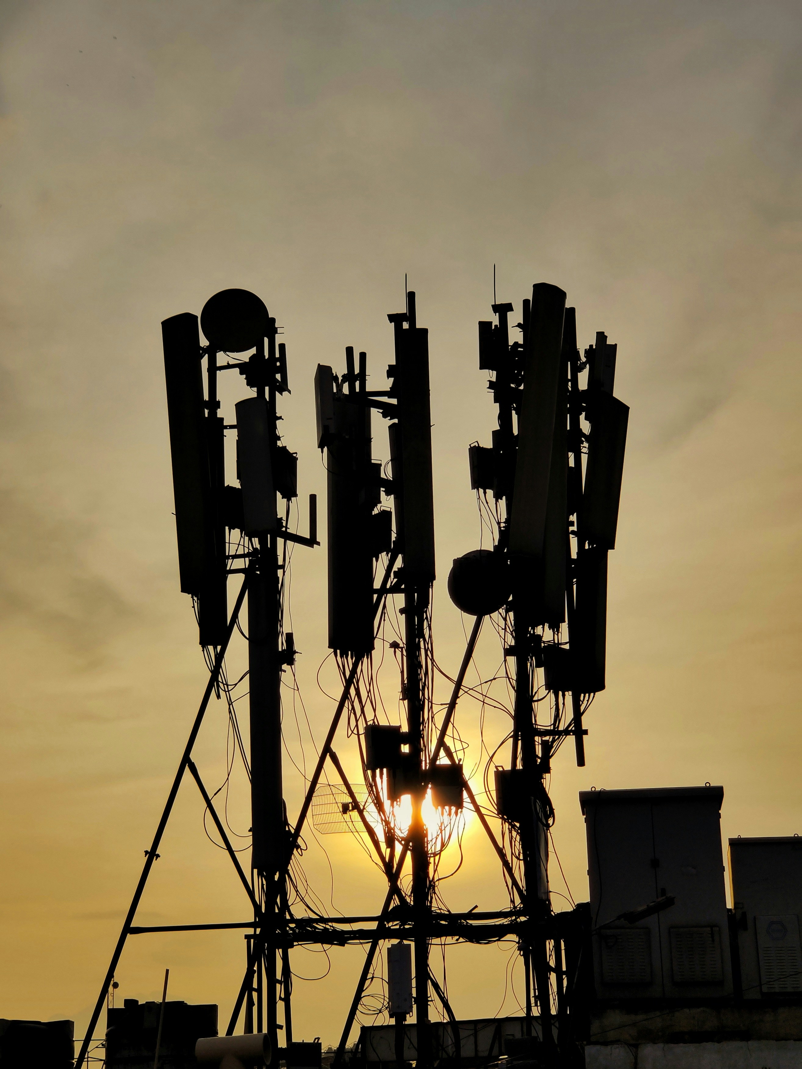 The sun is setting behind a tower of cell phones photo – Free Bengaluru ...