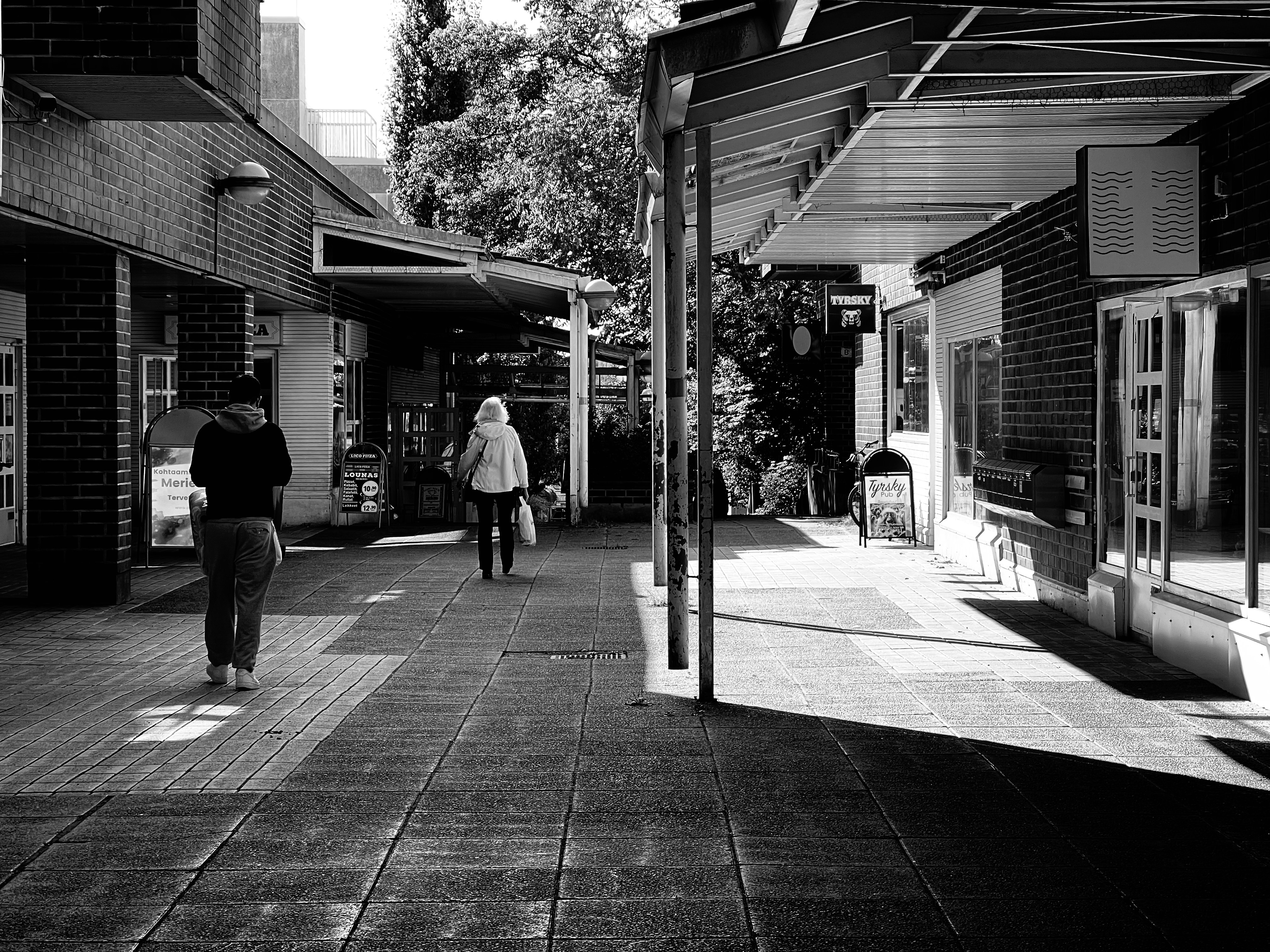 Monochrome Corridor: Quiet Figures in a Brick Arcade
