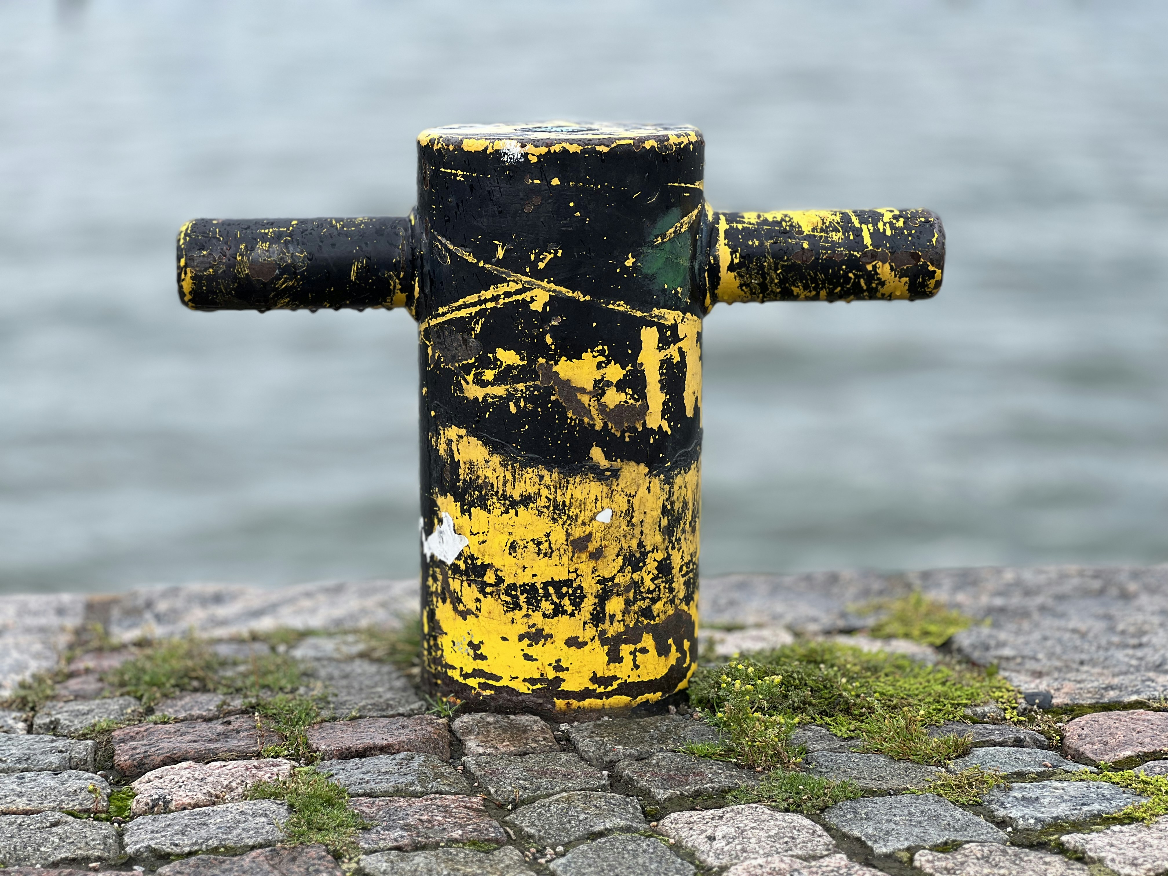 Weathered Harbor Bollard Guarding Mossy Cobblestones