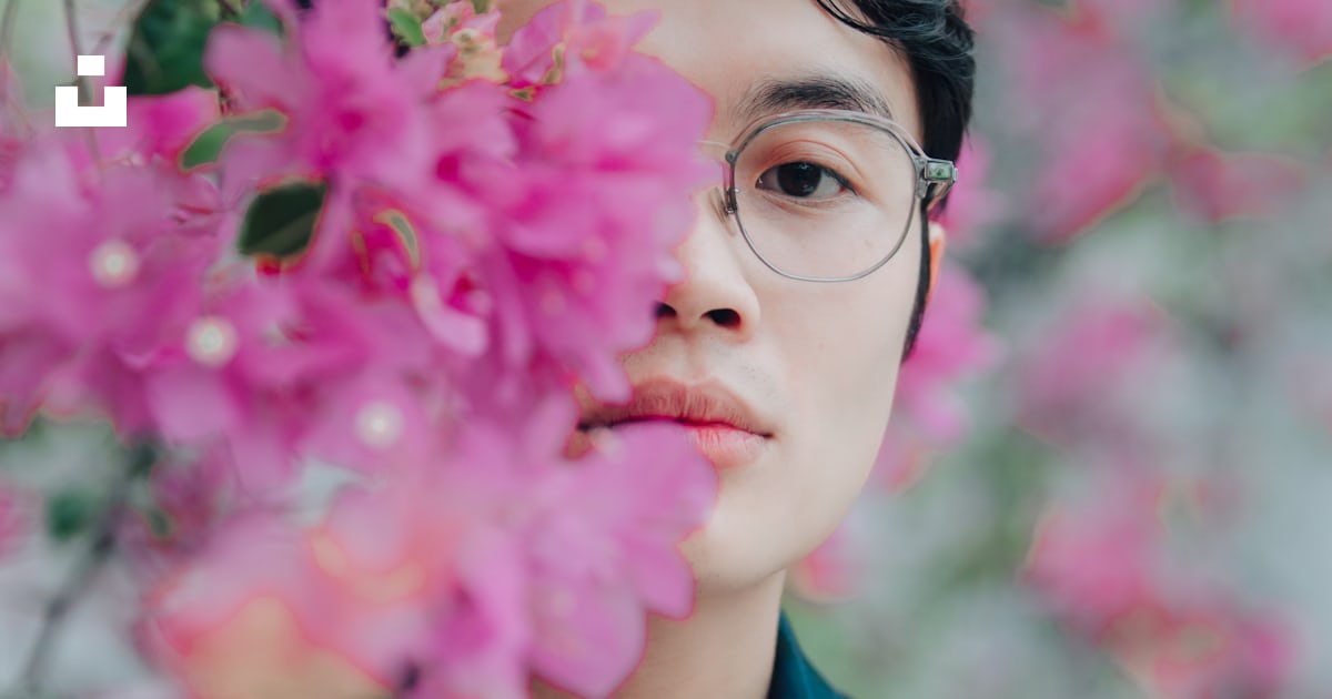 분홍색 꽃이 있는 나무 아래에 서 있는 안경을 쓴 남자 사진 Unsplash의 무료 베트남 이미지