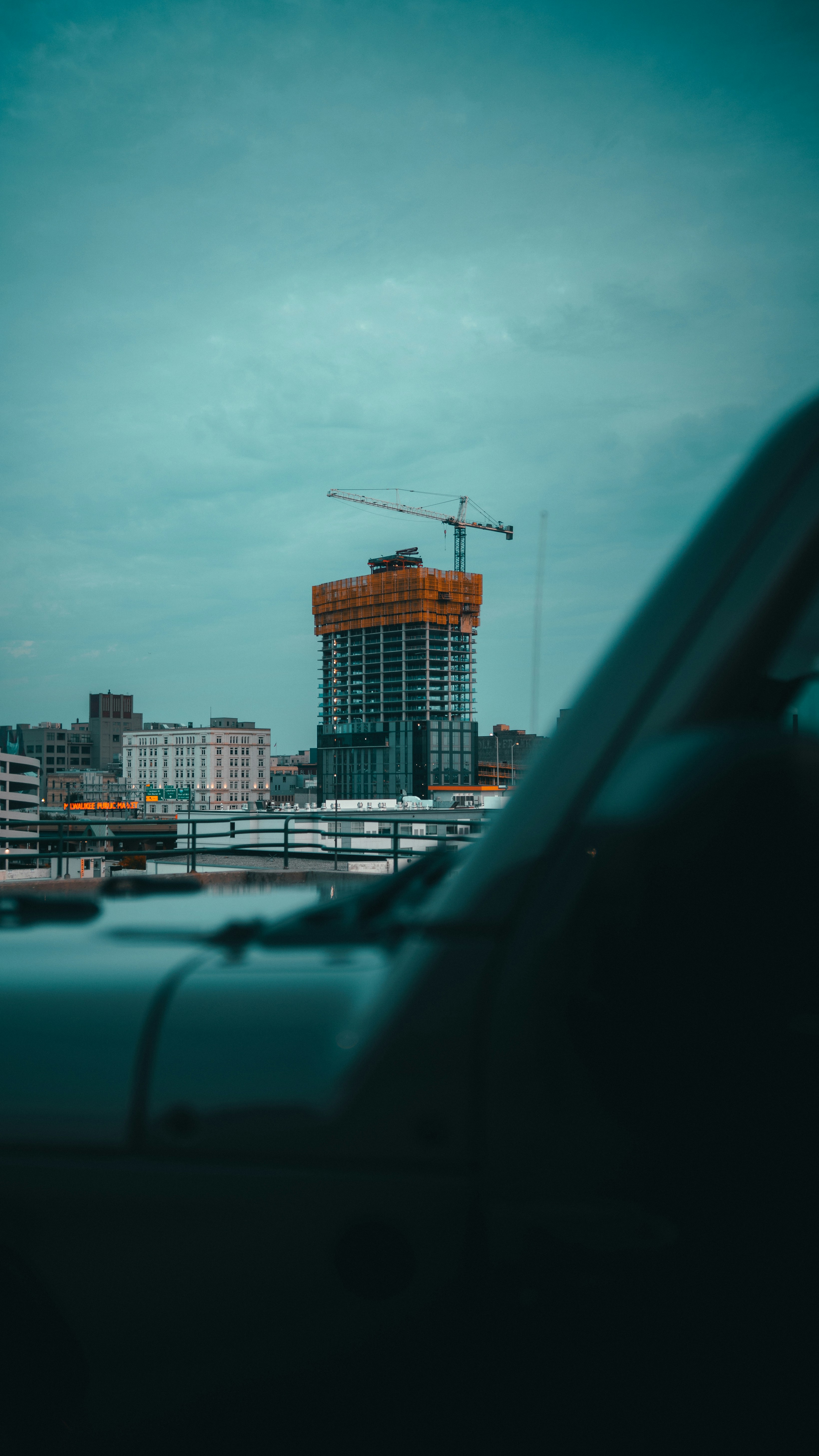Craned Skyline: Construction Arises Beyond a Car Window Frame