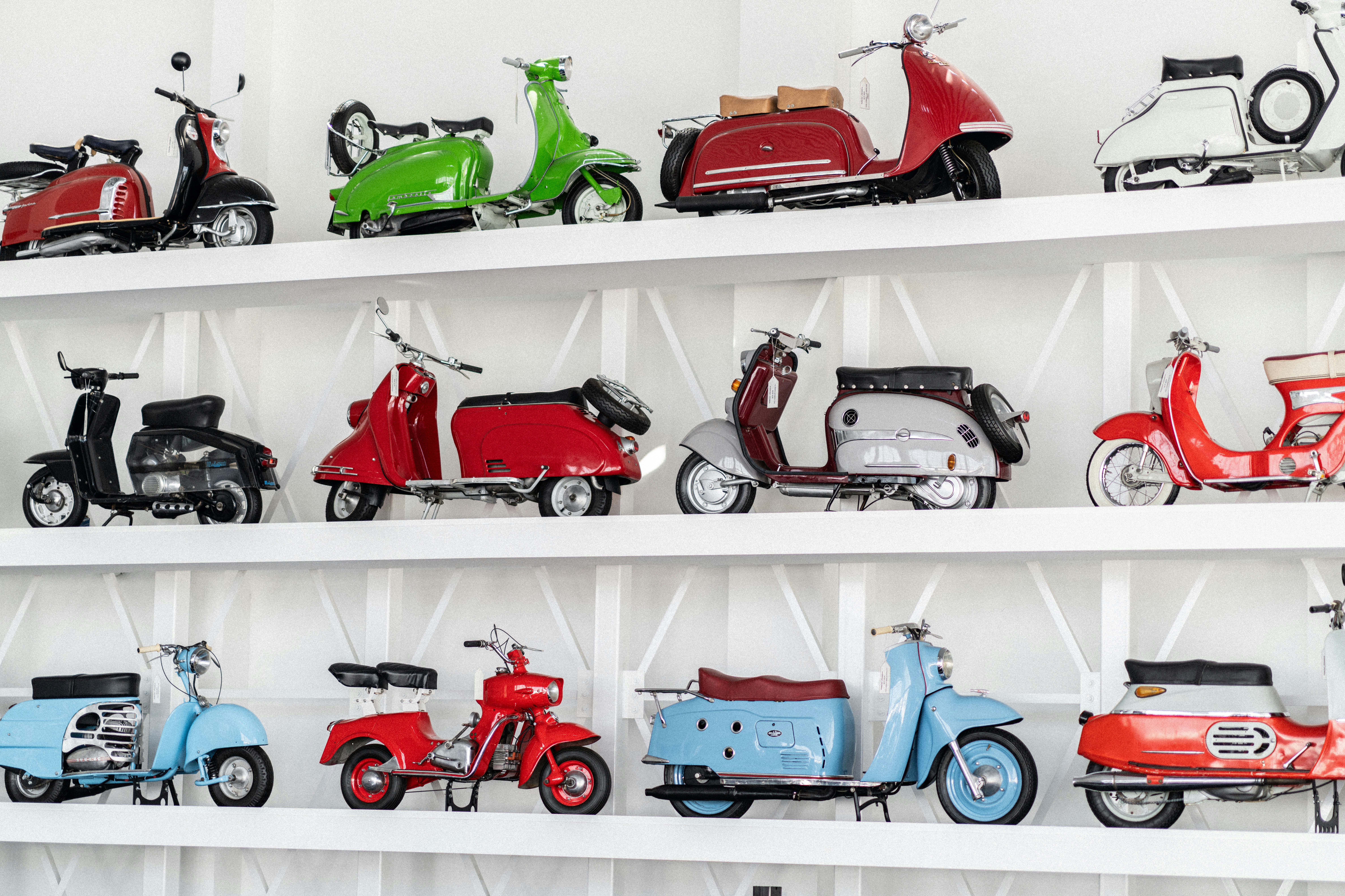Miniature Vespa Ensemble: Neon Scooters on Tiered White Shelves