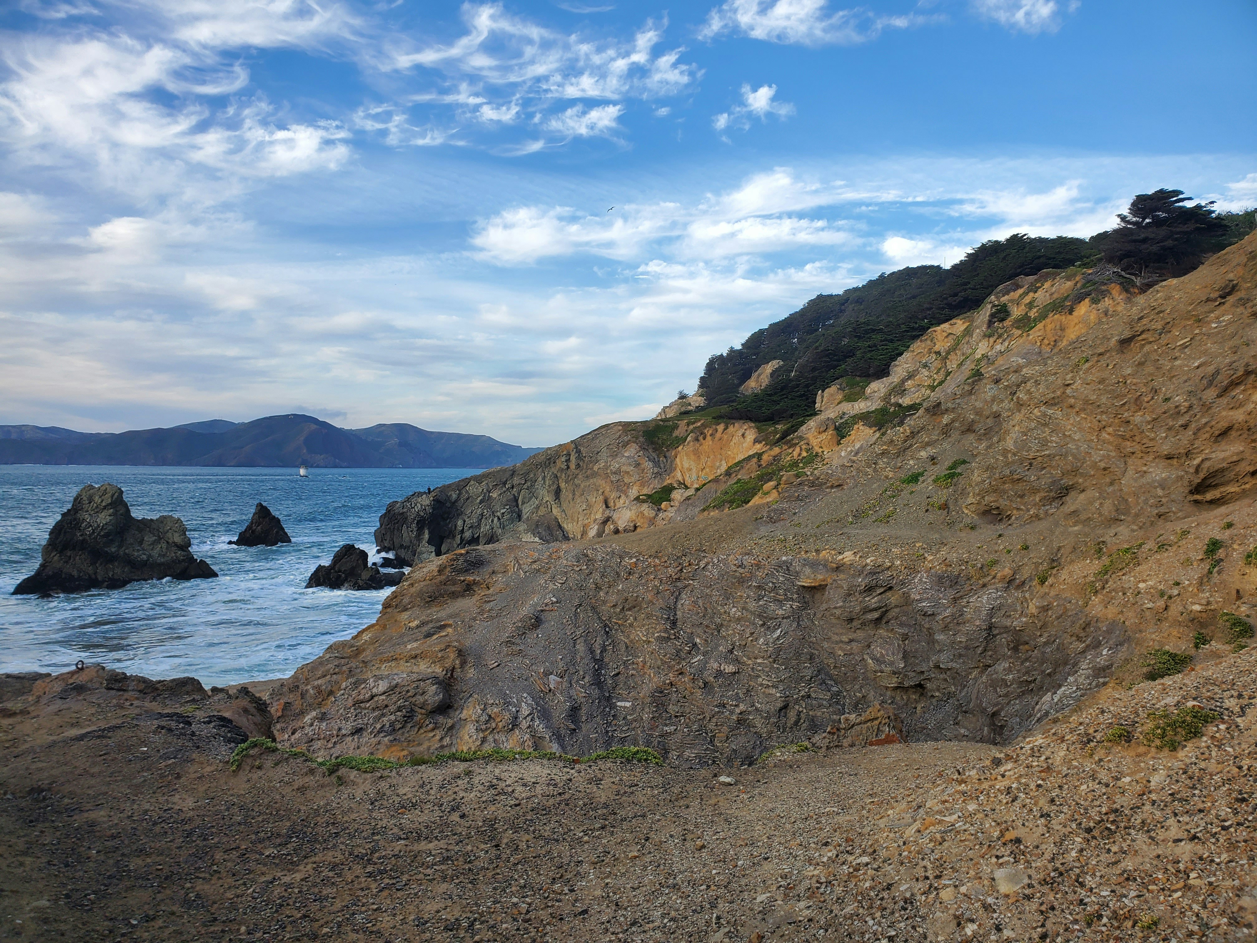 A bench sitting on the side of a cliff next to the ocean photo – Free ...