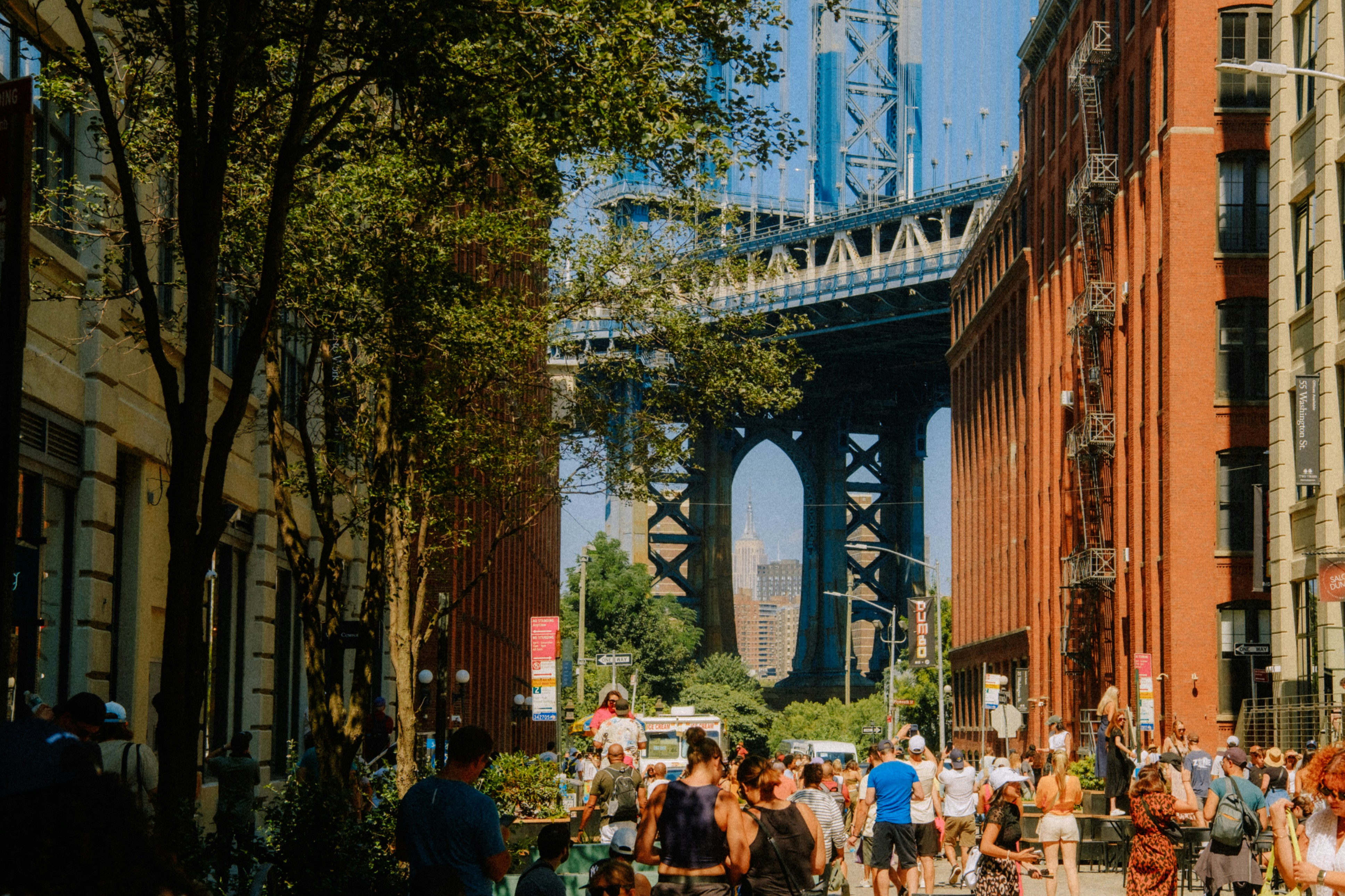 Under the Arch: A Sunlit City Crowd Traverses a Brick-Block Street