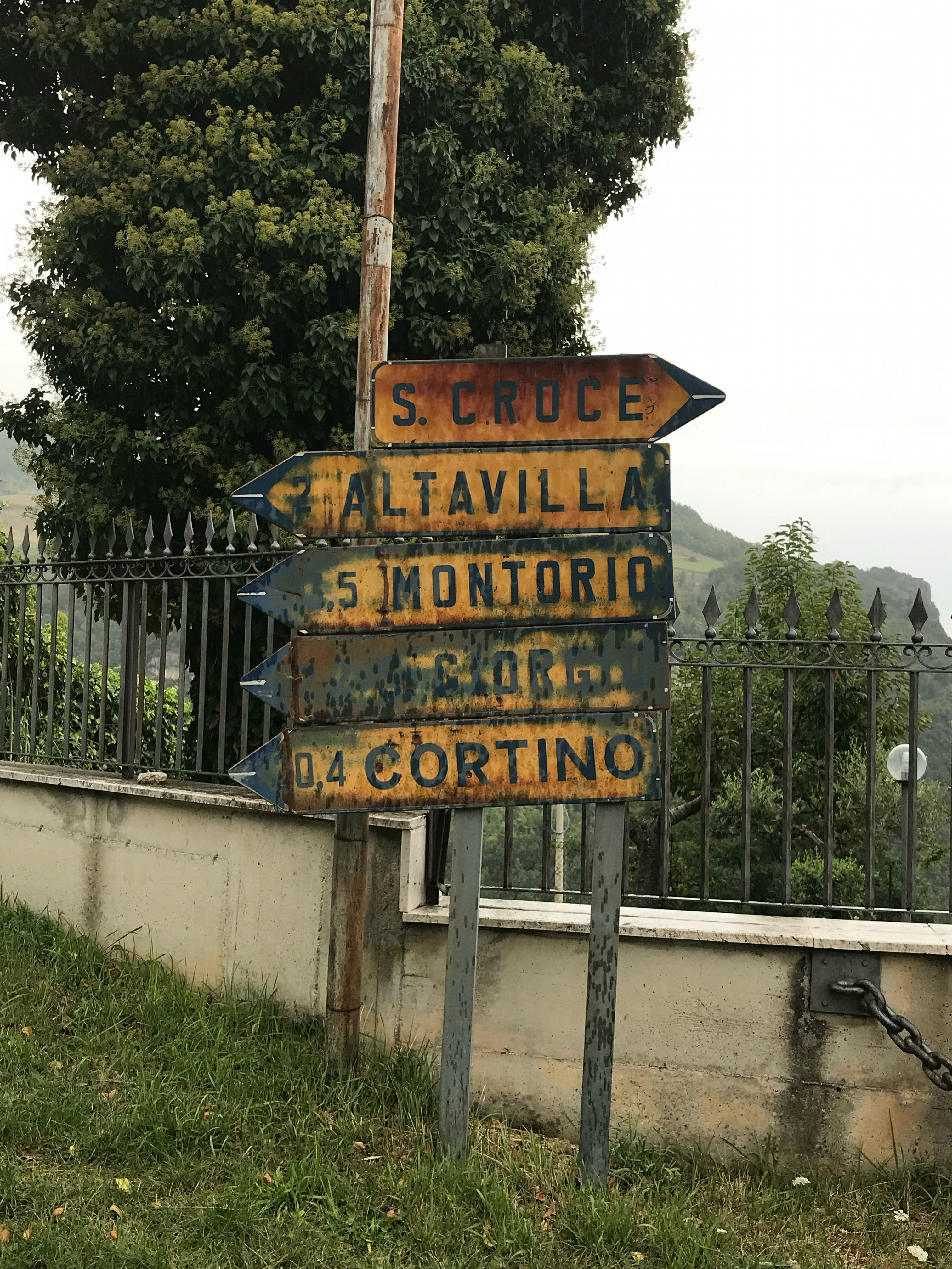 A rusted street sign sitting on the side of a road photo – Free Italy ...
