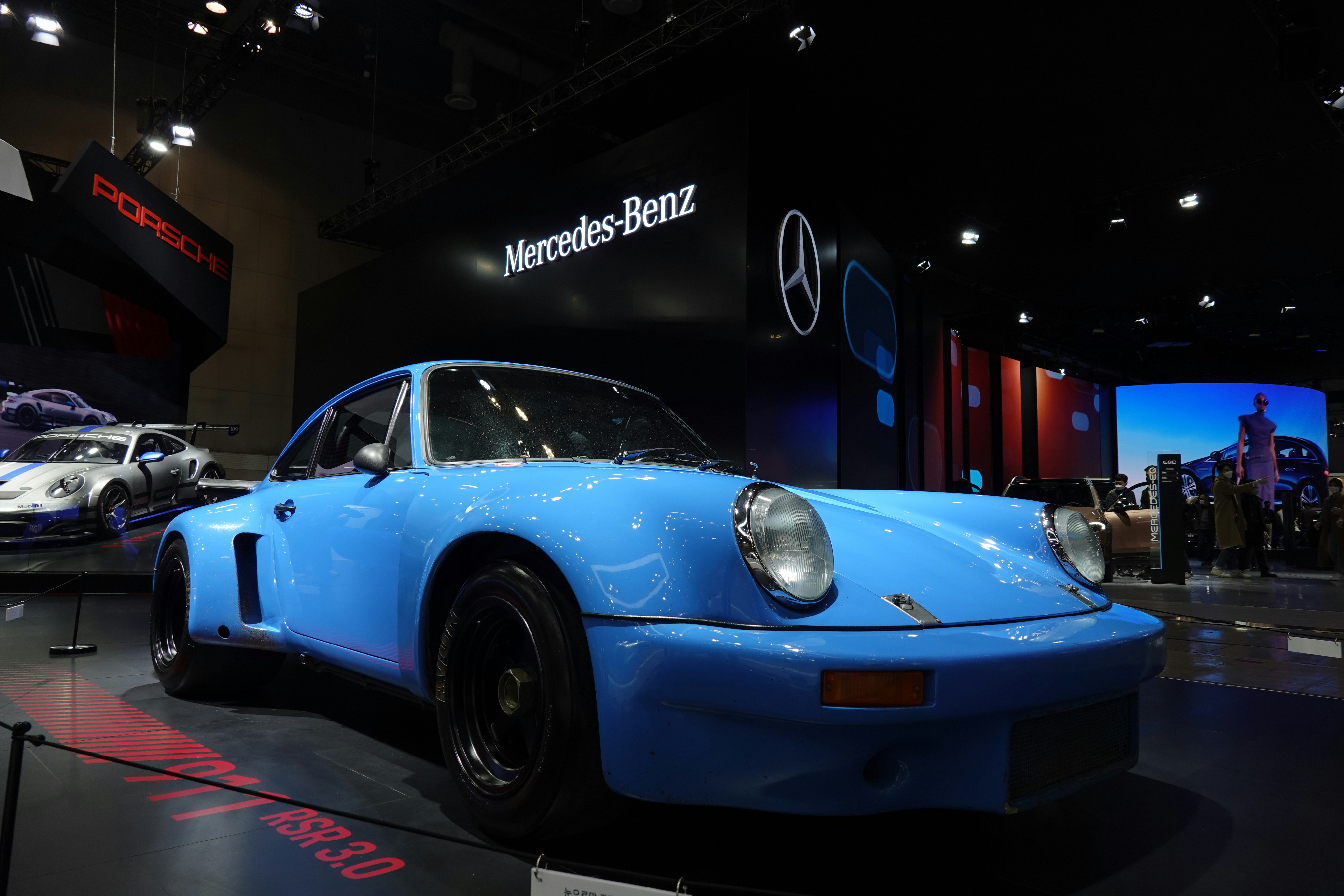 Electric Blue Porsche 911 on a Neon-Illuminated Auto Show Floor
